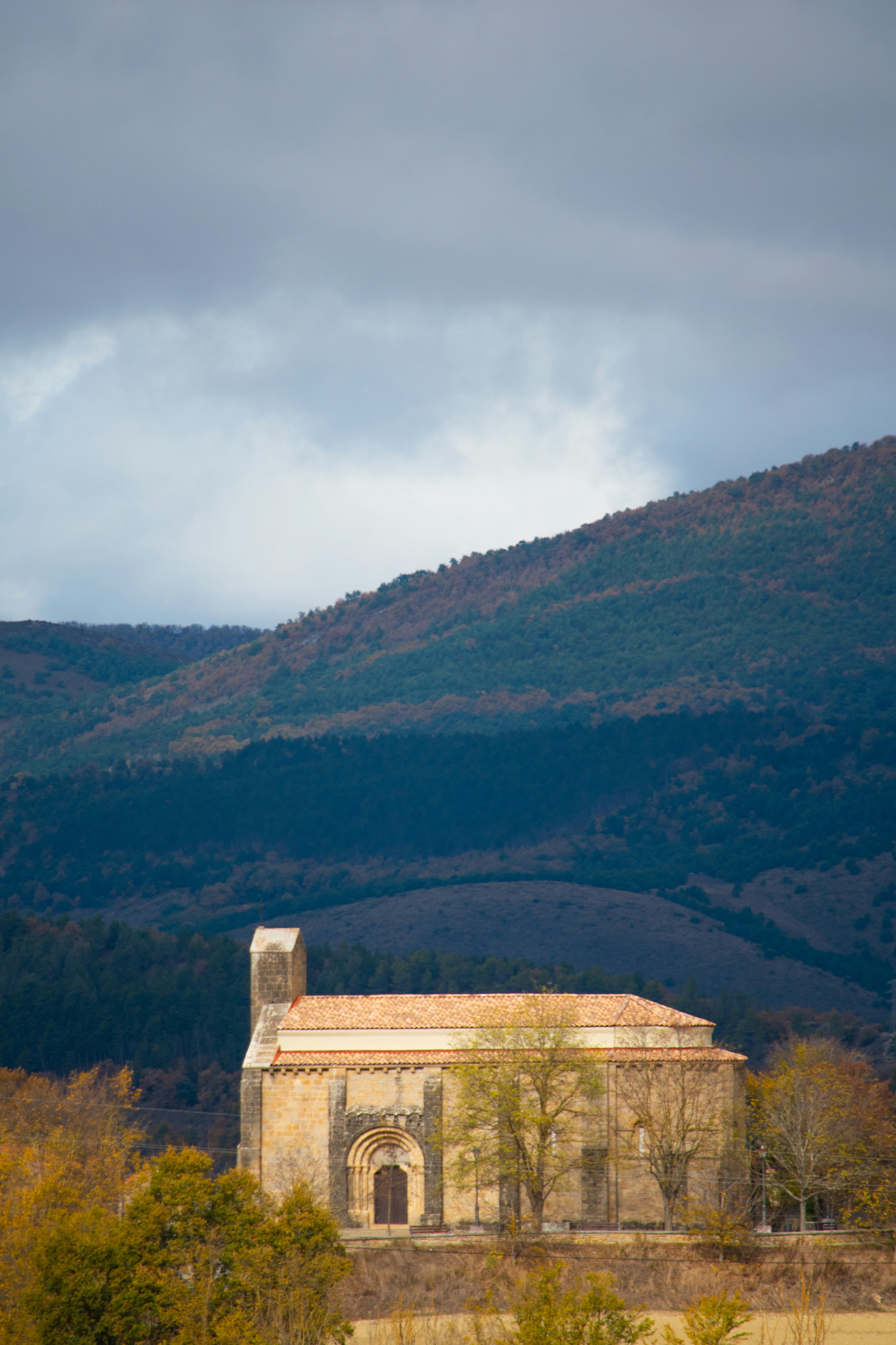 A church in the middle of a field with a mountain in the background ...