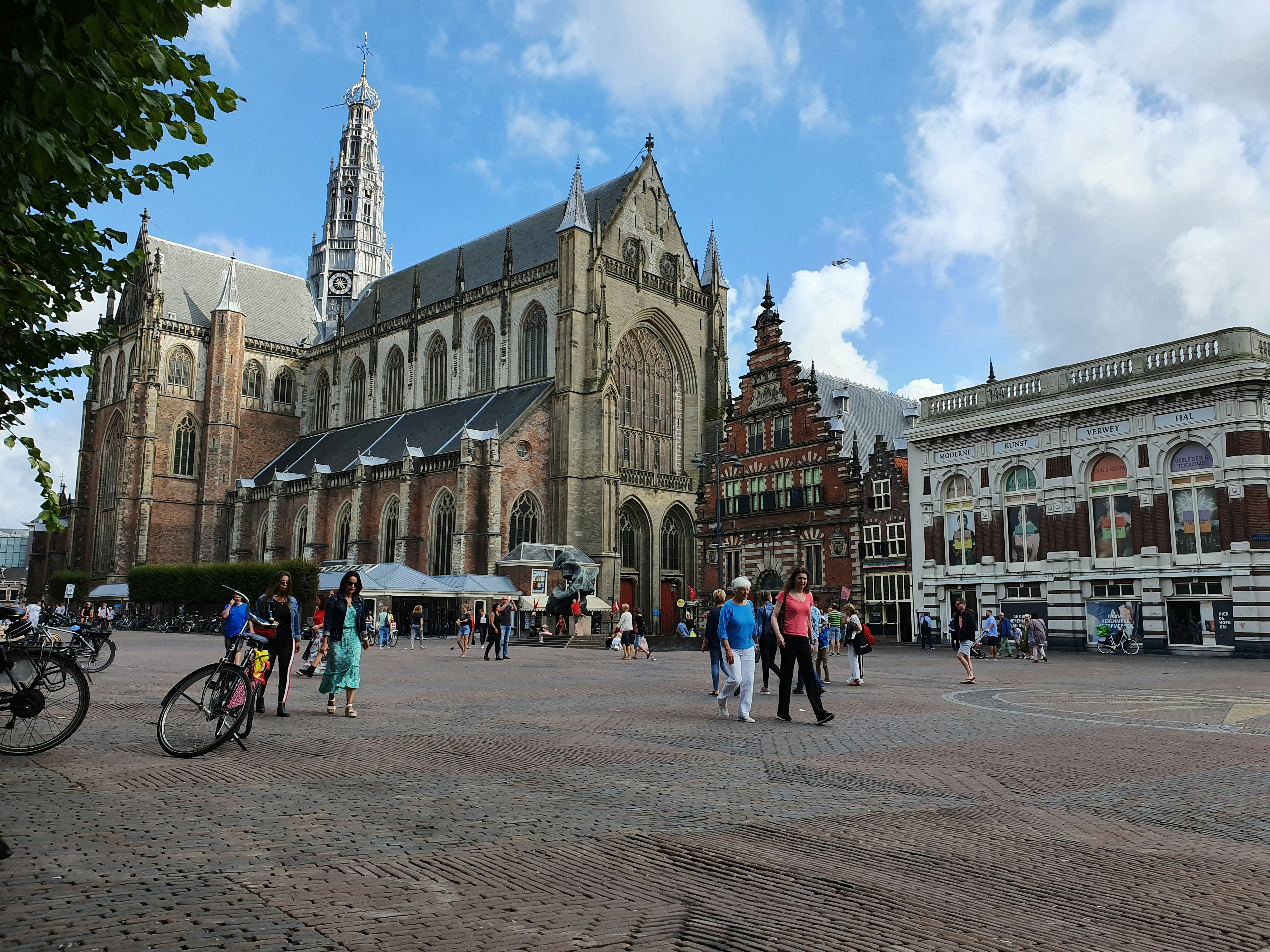 People walking near a grand historic church in a bustling square.