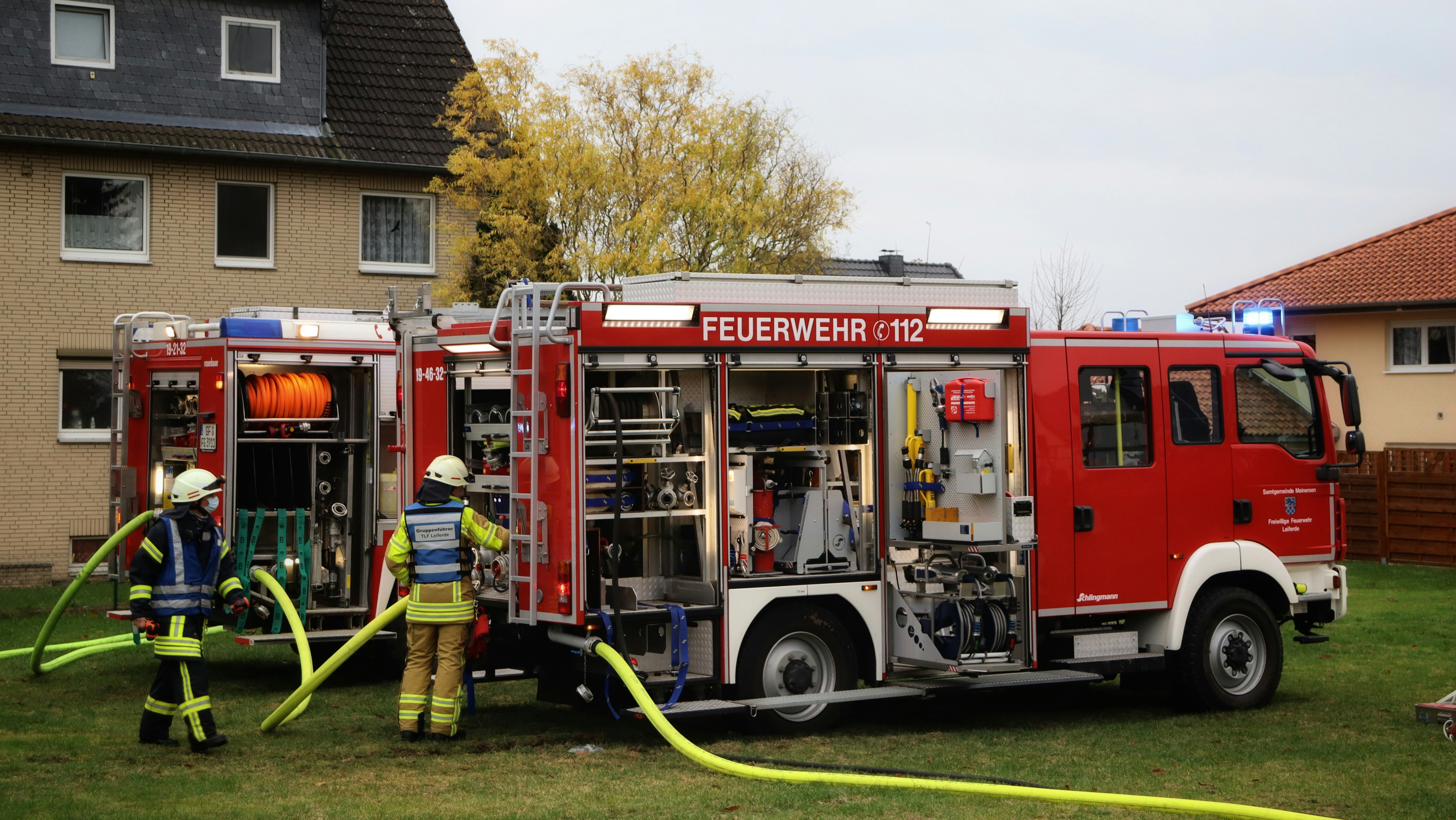 Suburban Fire Engine Response: Crews Unspool Hoses on a Green Lawn