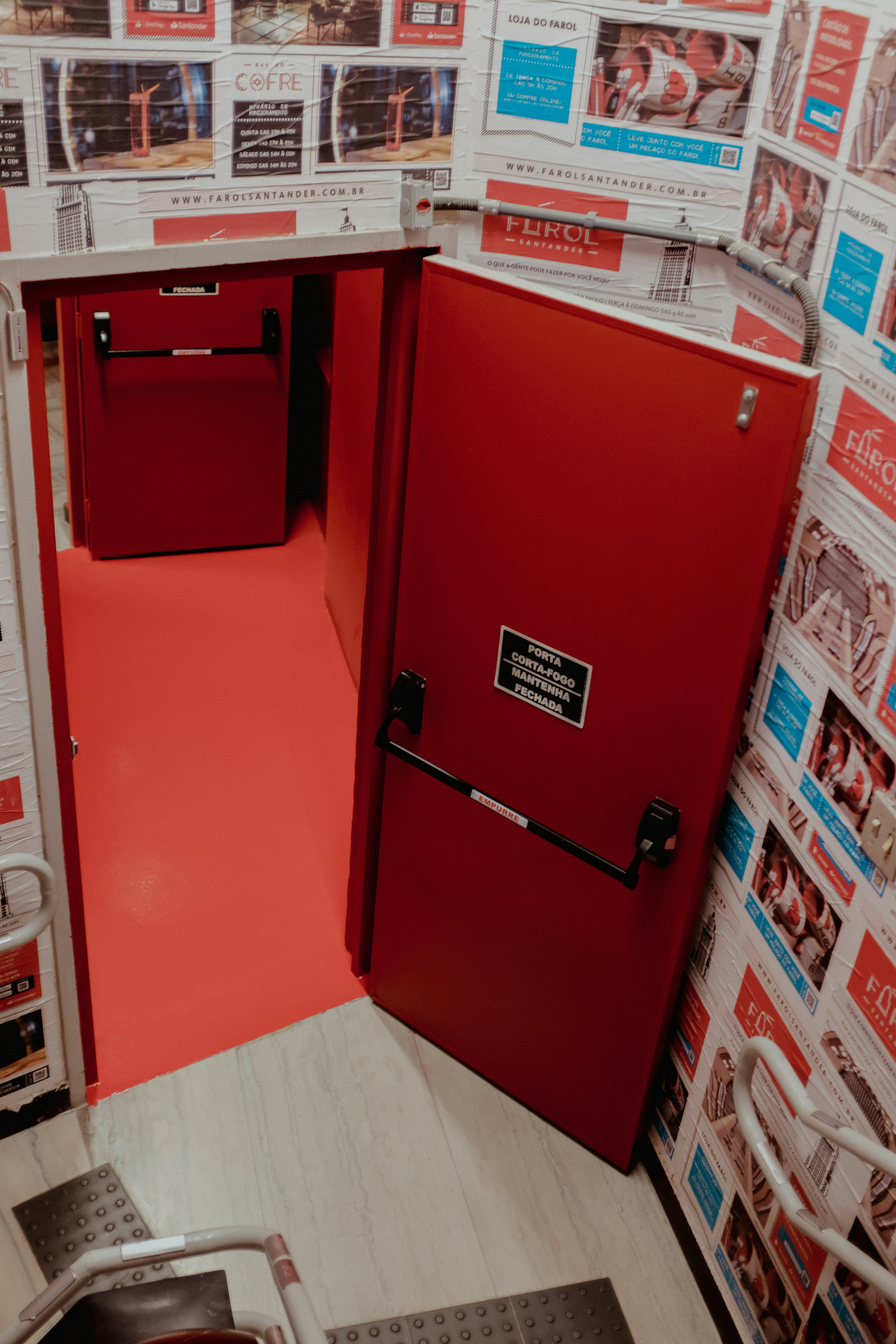 Bright red emergency exit door in a corridor adorned with safety posters and a vivid floor. A stark reminder of safety protocols.