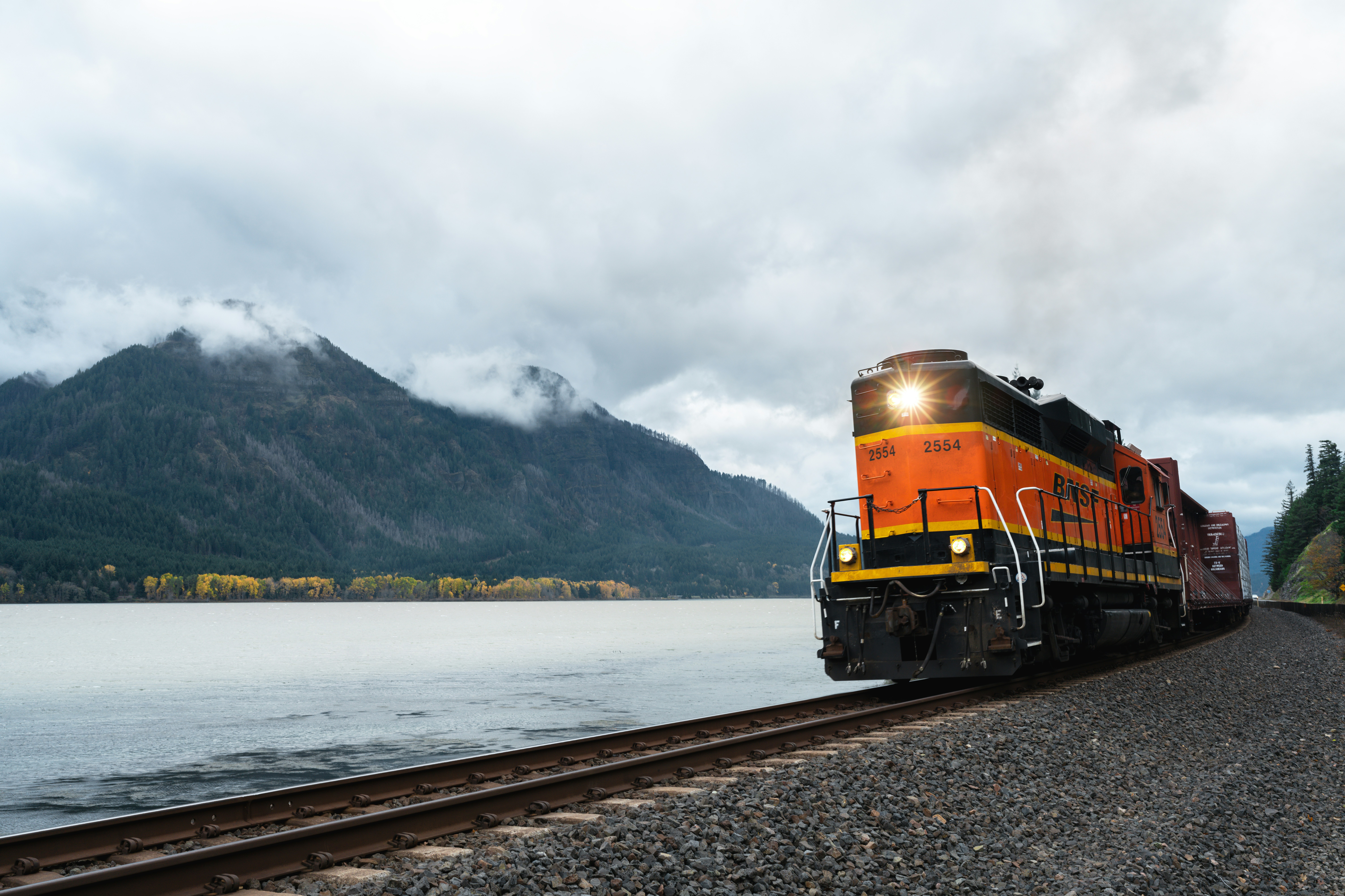 A train traveling down train tracks next to a body of water photo ...