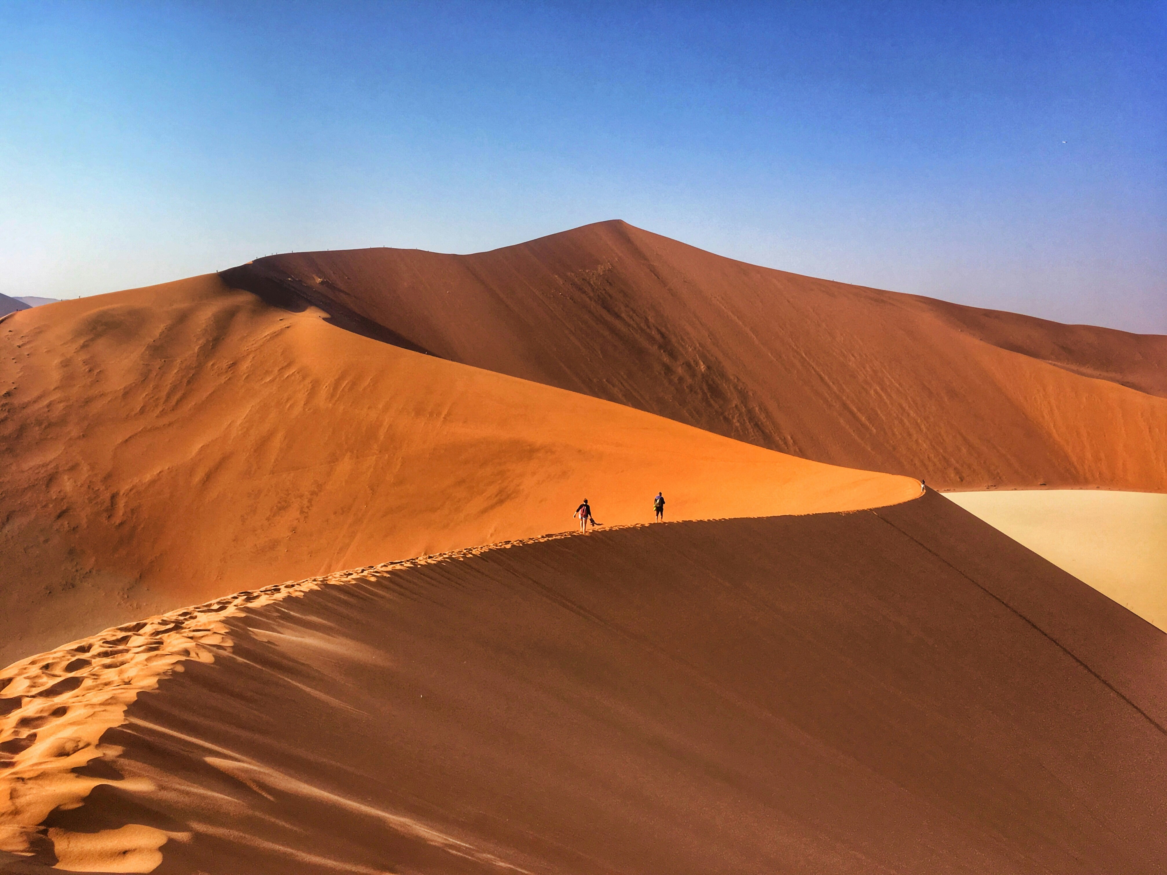 Dune at Sossusvlei, Namibia | two people walking up a sand dune in the desert