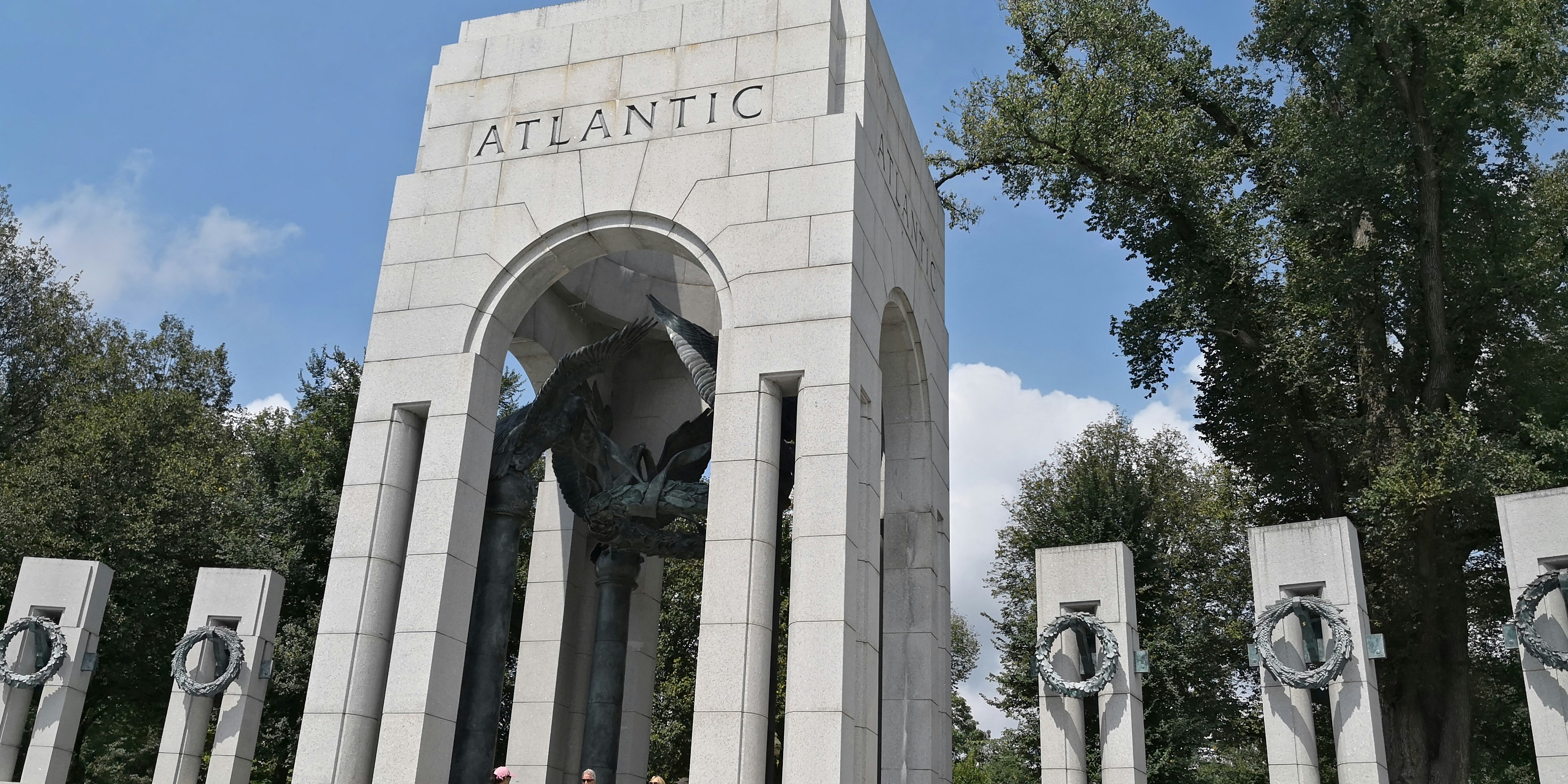 Monument dedicated to the Atlantic Theater, featuring a grand arch and surrounding pillars adorned with wreaths. The structure symbolizes honor and remembrance.