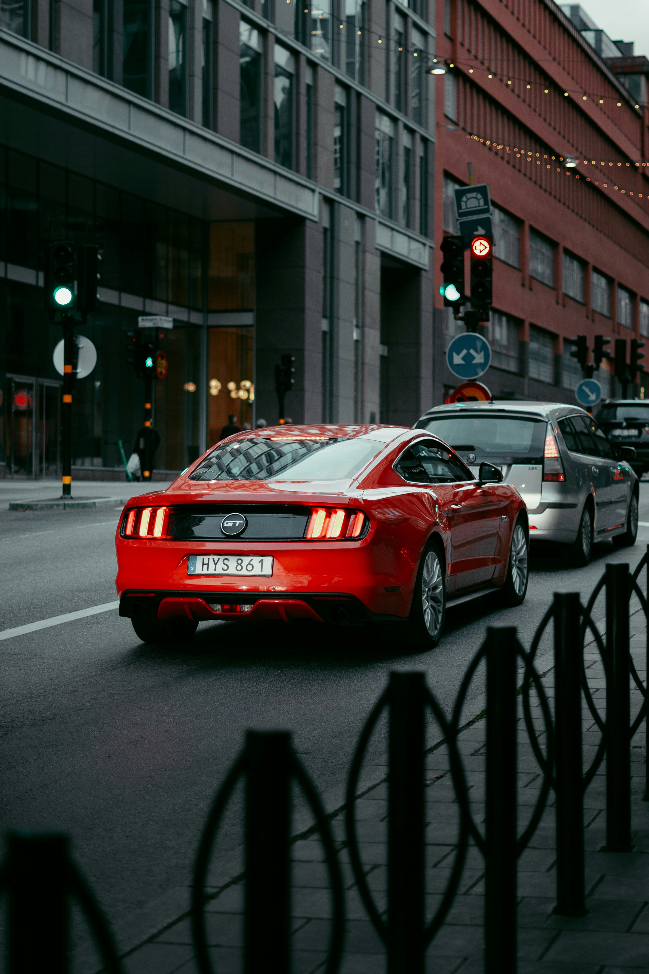 Crimson Mustang Coasting Through a Glass-Lined City Street