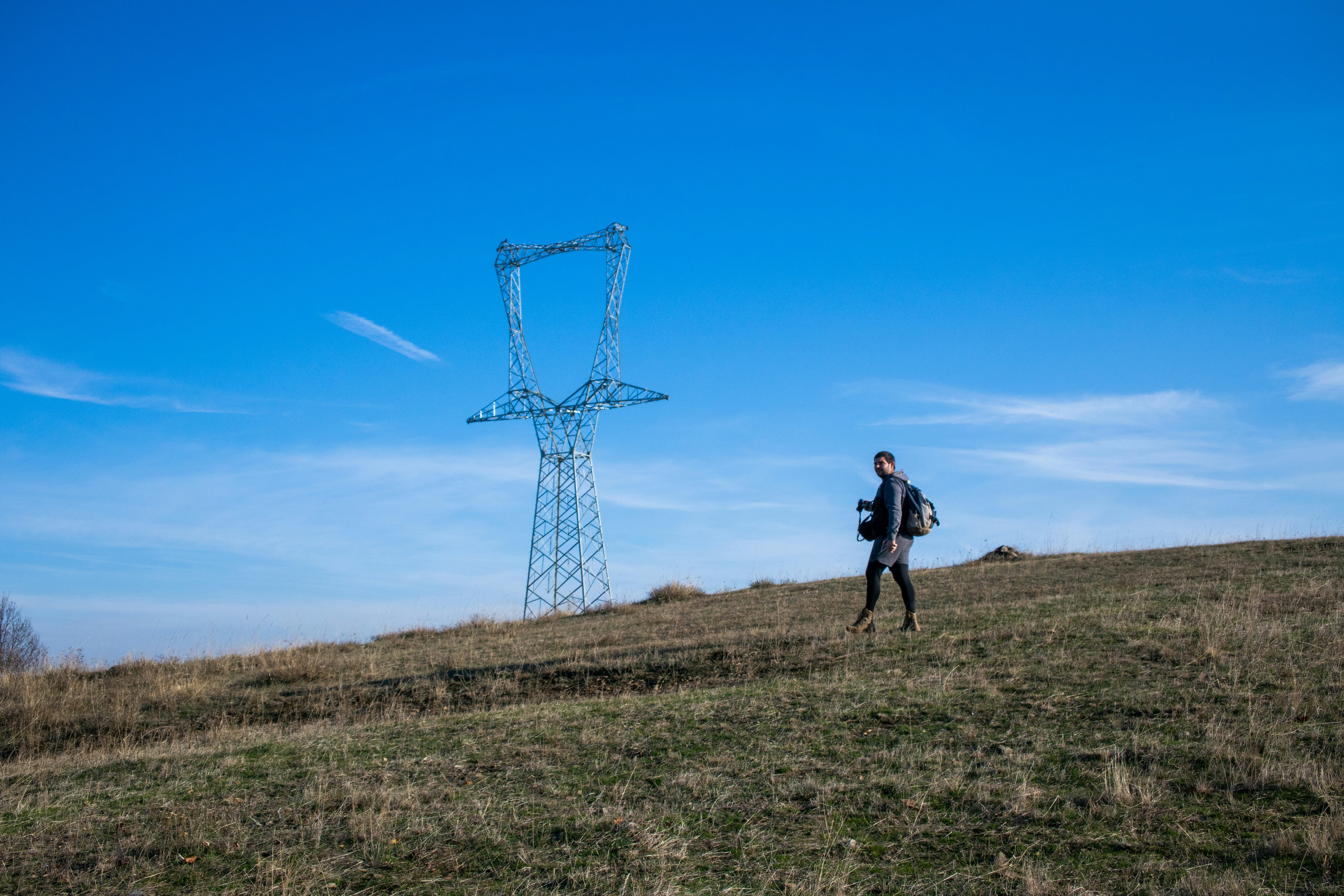 a man standing on top of a grass covered hill