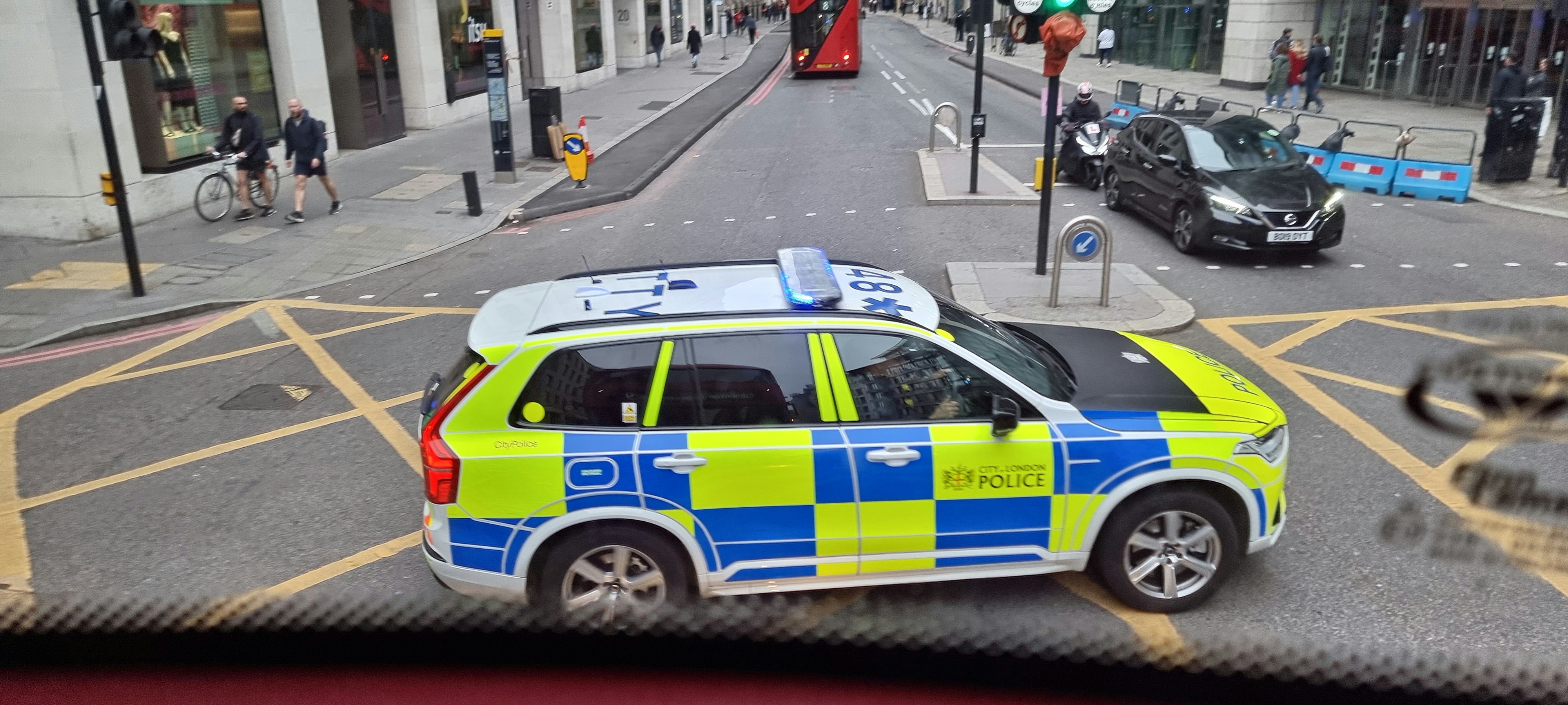 A yellow and blue police car driving down a street photo – Free Person ...