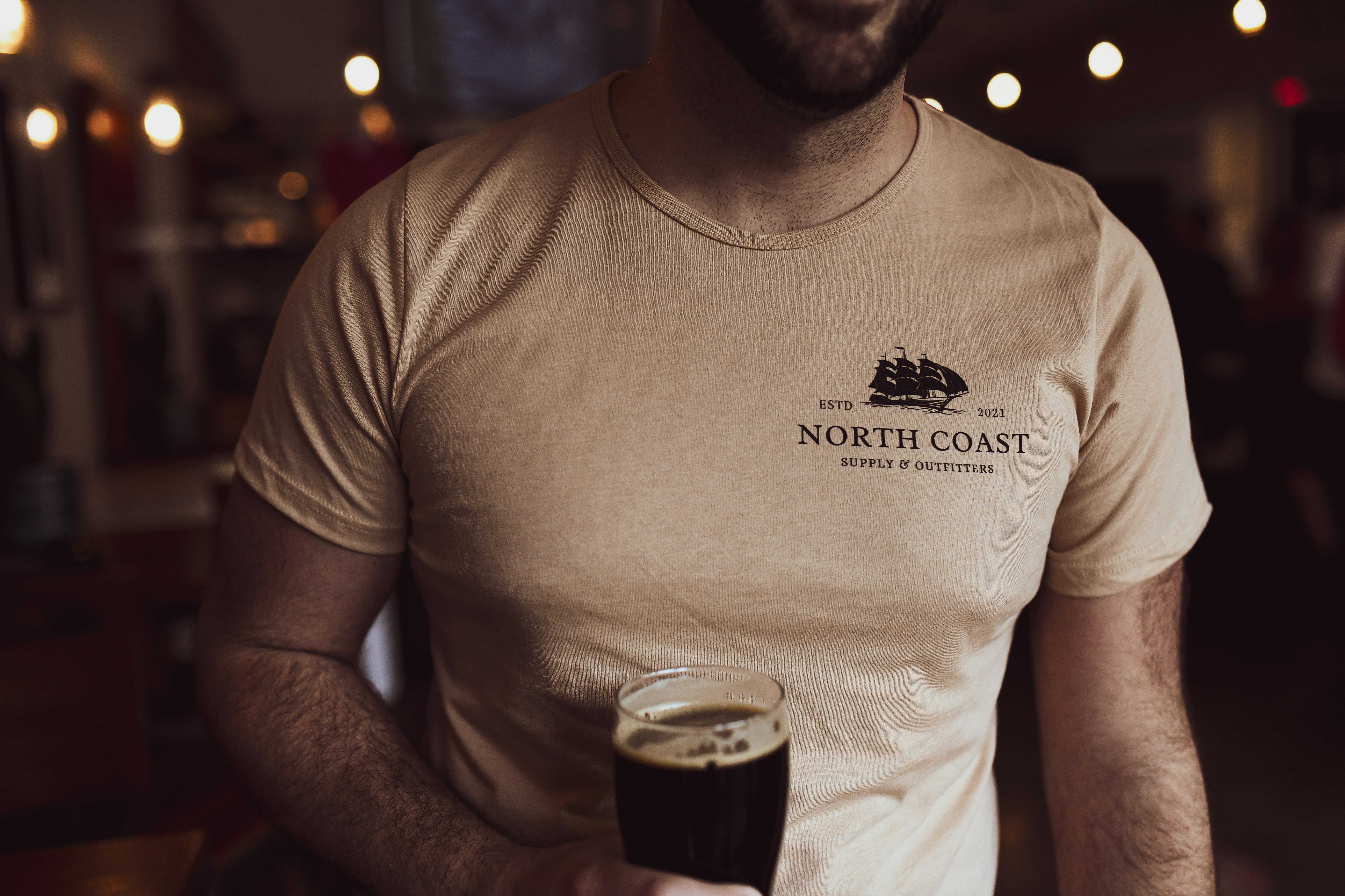 Amber Glow and Quiet Toast: North Coast Tee in a Dim Bar