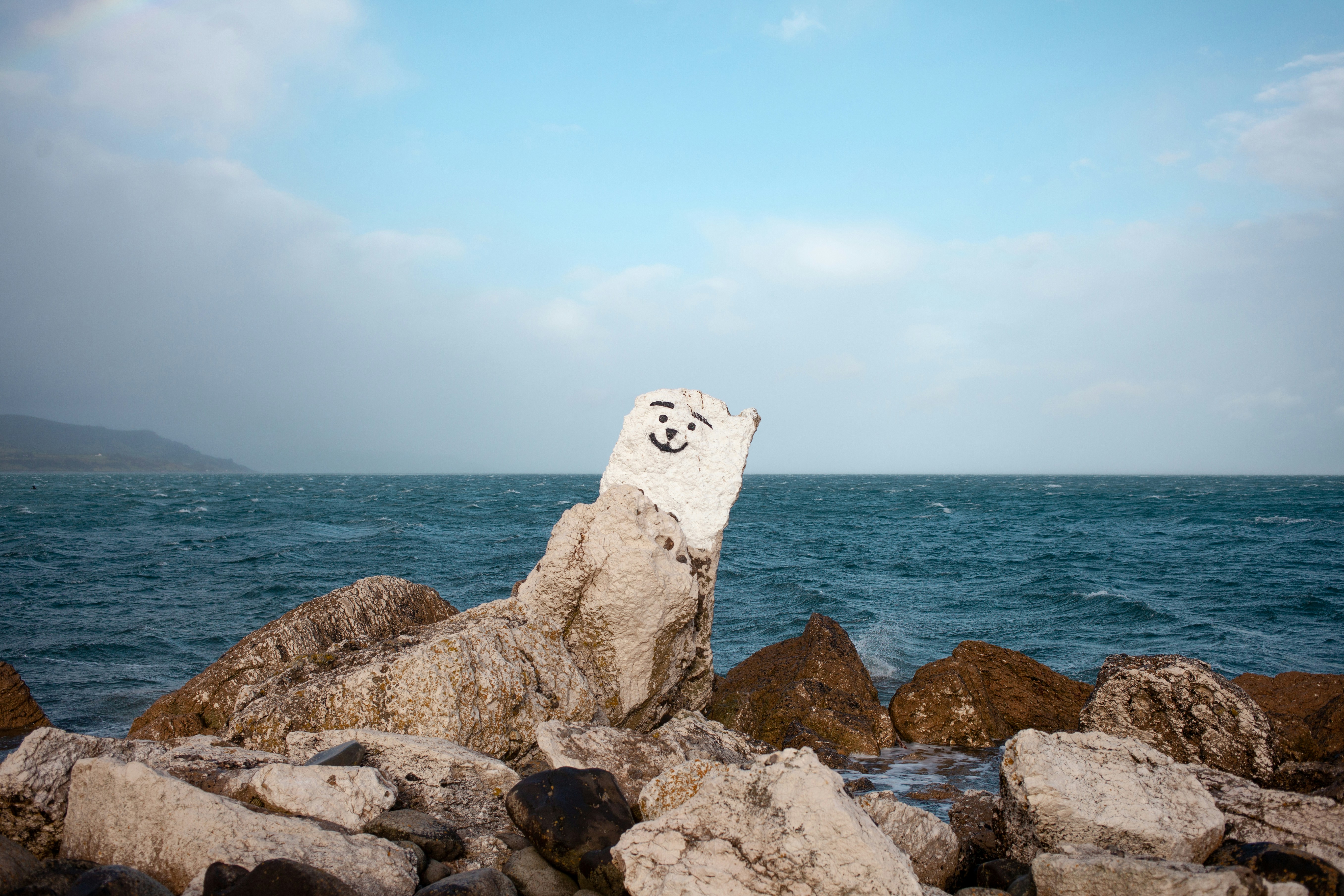 Coastal Mascot on the Breakwater: A White Plush Sentinel