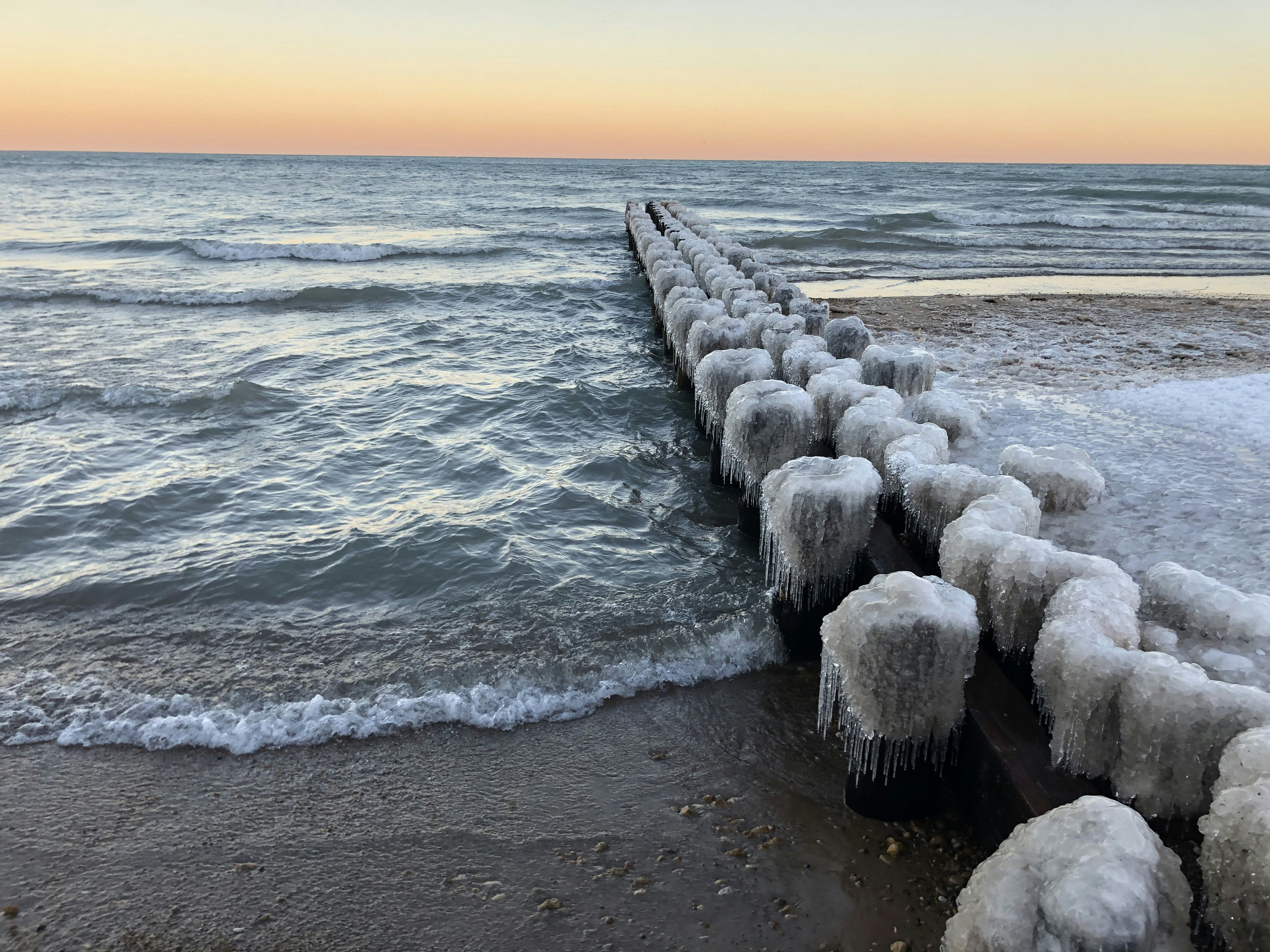 A long line of ice - covered posts on the shore of a beach photo – Free ...