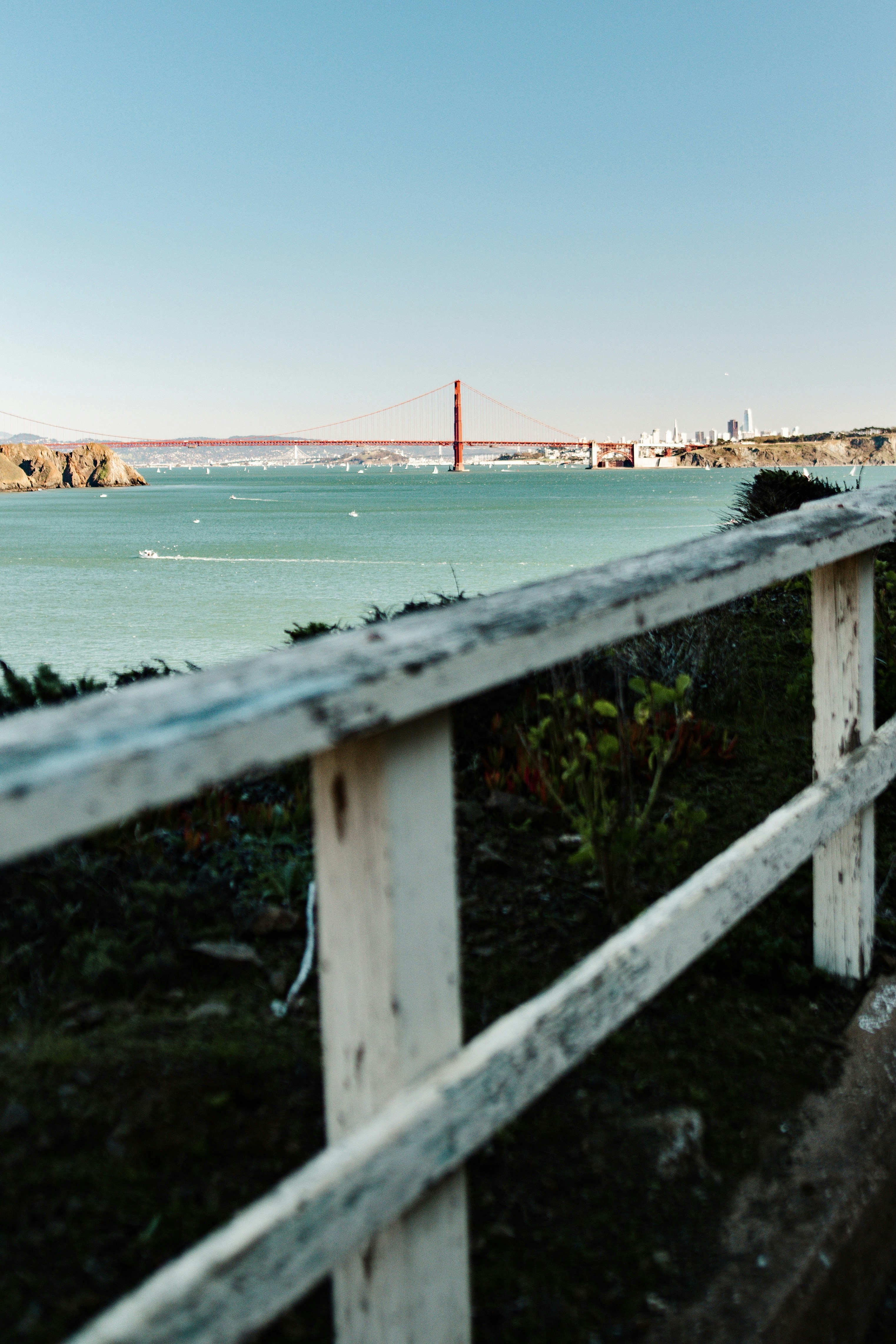 Red Suspension Bridge Framed by a Weathered Fence Over Bay Waters
