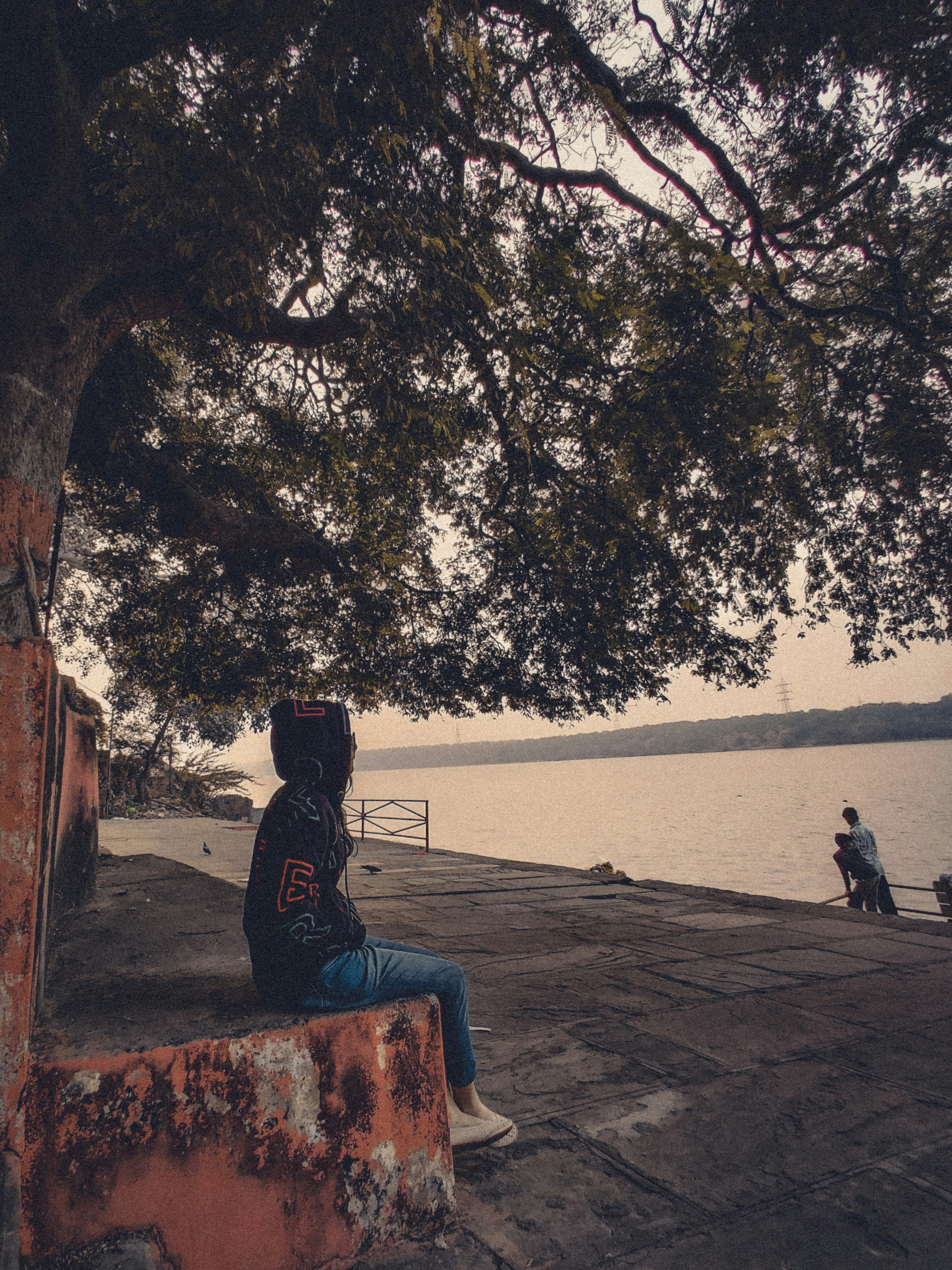 a person sitting on a wall next to a body of water