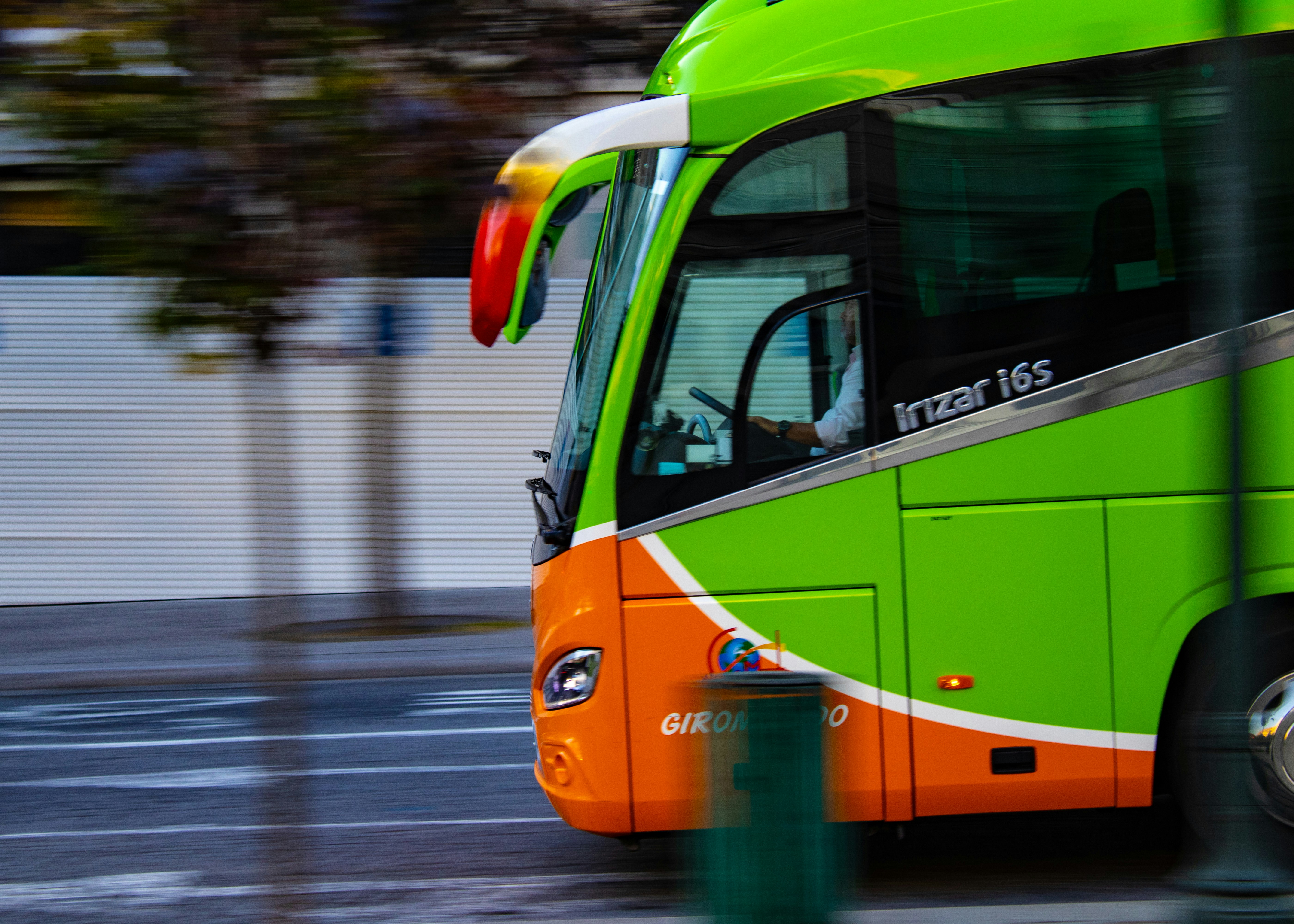 A green and orange bus driving down a street photo – Free Portugal ...