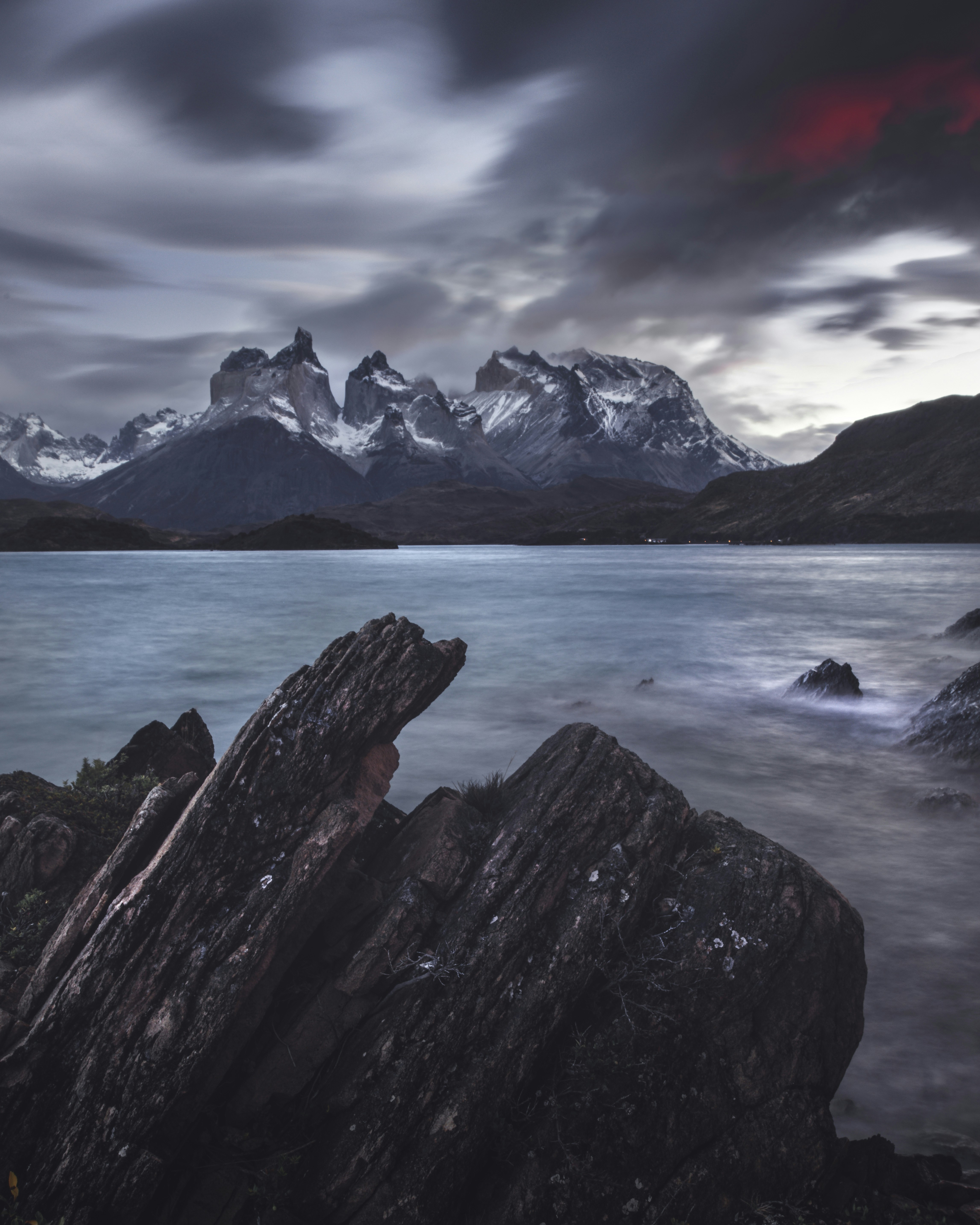 Rocks at the Fjord's Edge Beneath Looming Glacial Peaks at Dusk