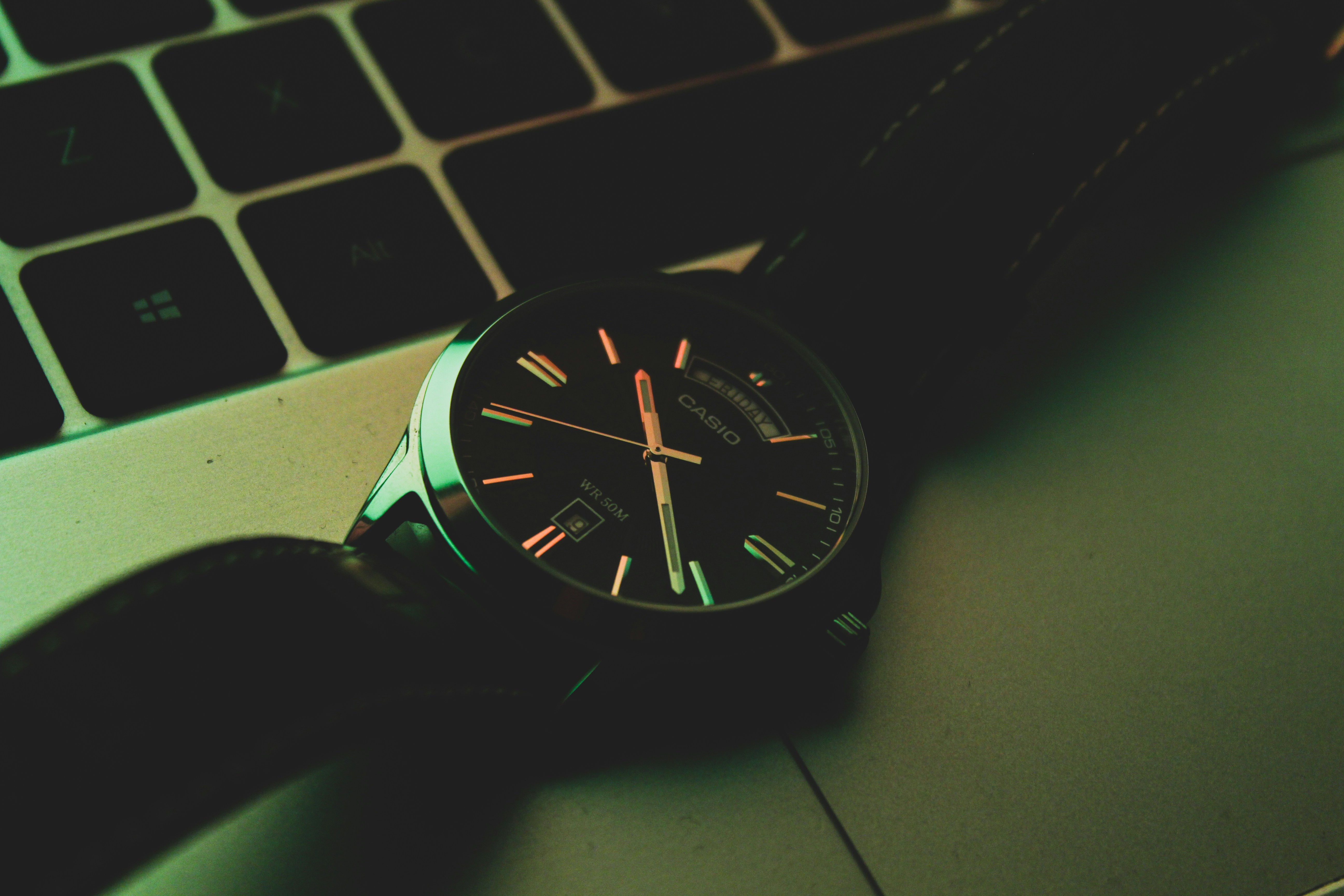 A sleek Casio watch resting on a laptop keyboard, highlighting the contrast between classic design and modern technology.