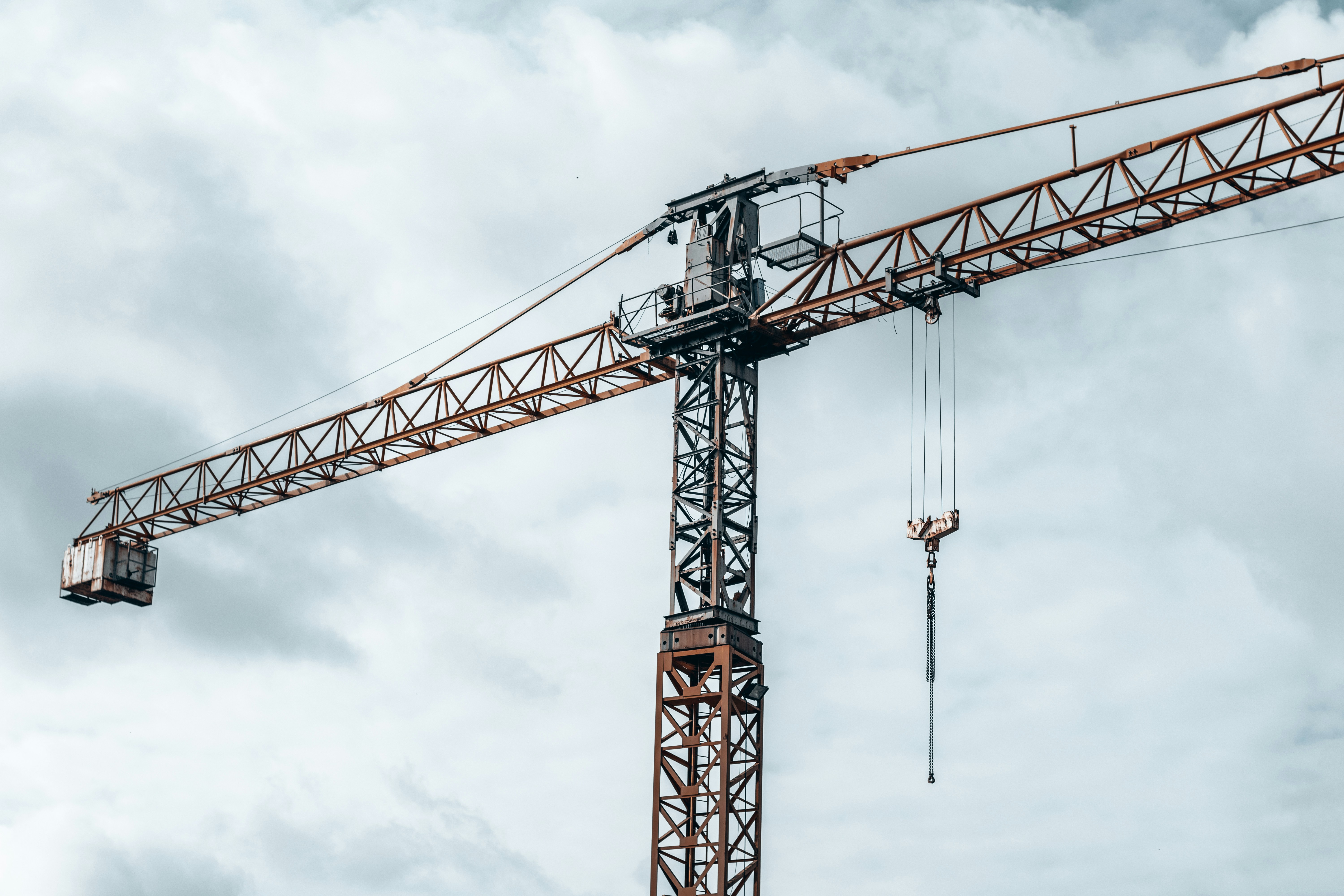 A large construction crane looms against a backdrop of cloudy skies, showcasing its intricate structure and machinery.