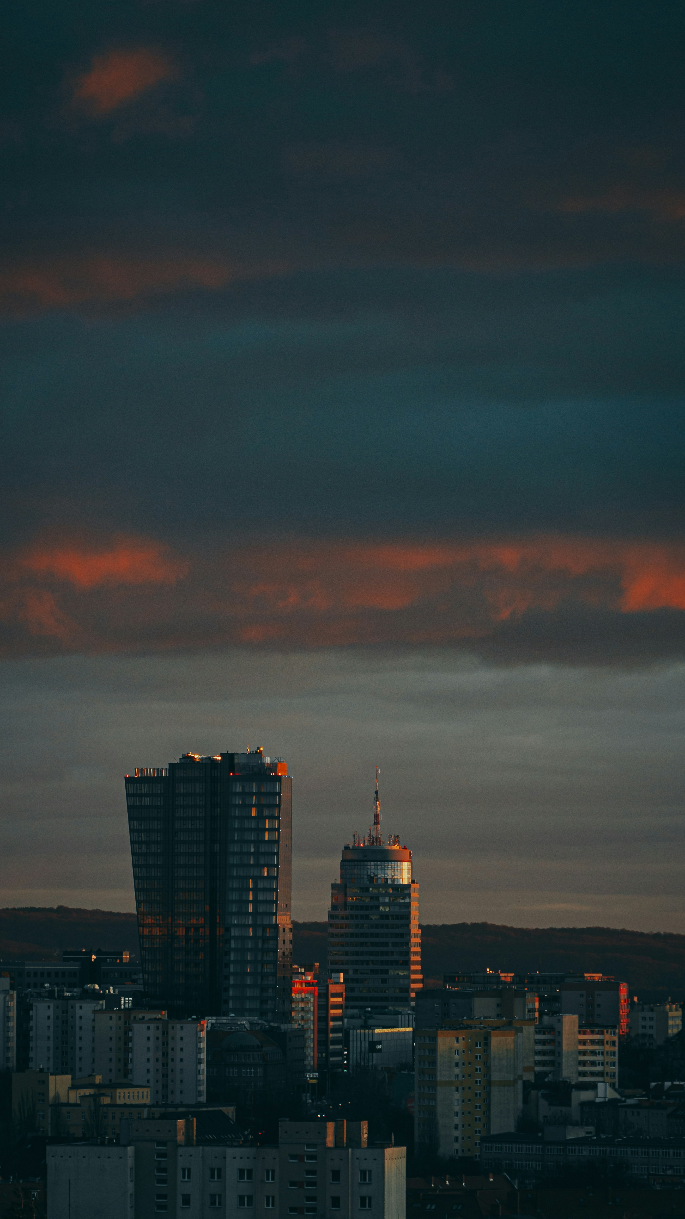 Modern skyscrapers silhouetted against a vibrant sunset sky, showcasing the interplay of architecture and nature's palette.