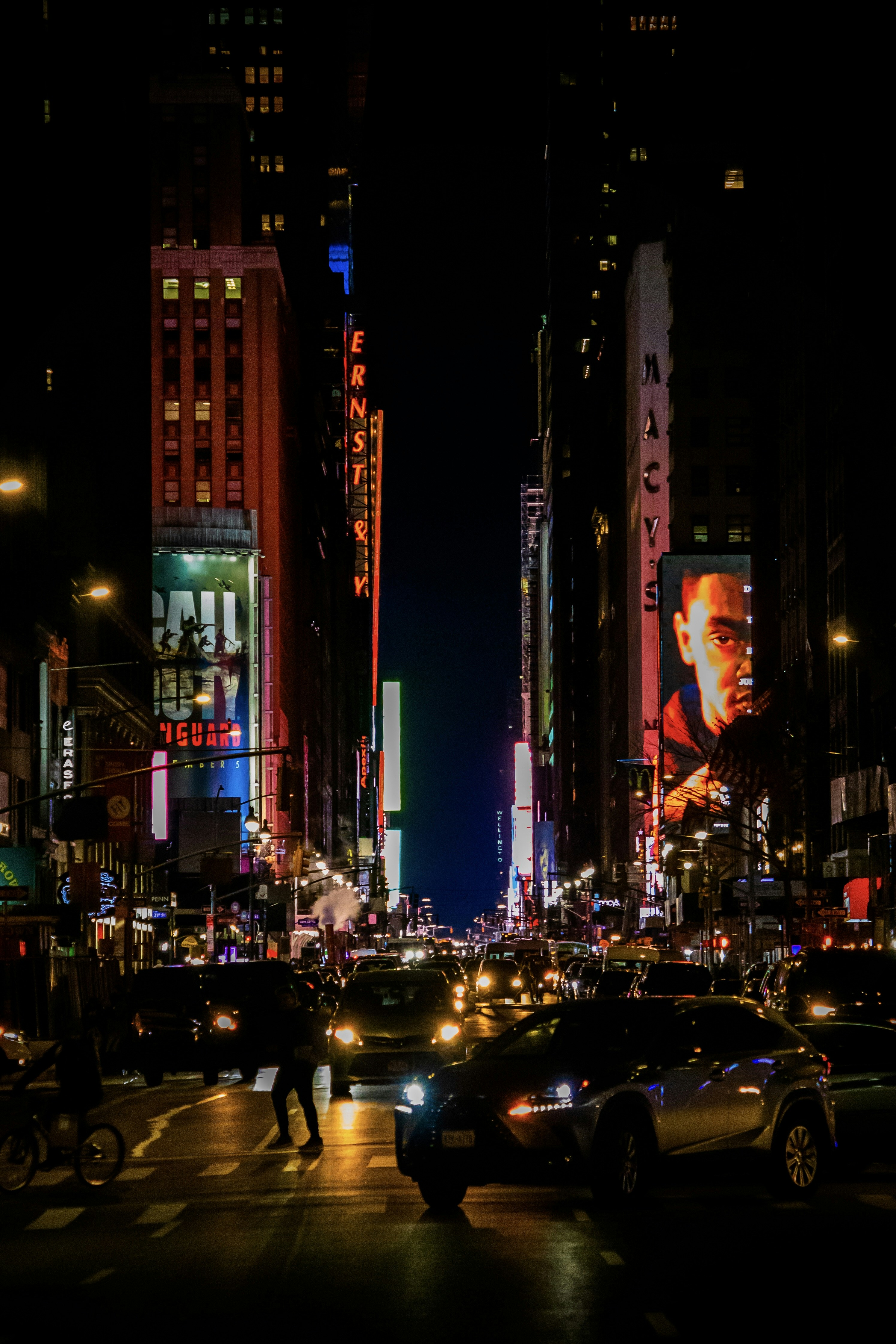 Vibrant city street illuminated by neon signs at night, showcasing bustling traffic and pedestrians. The scene captures the energy of urban life.