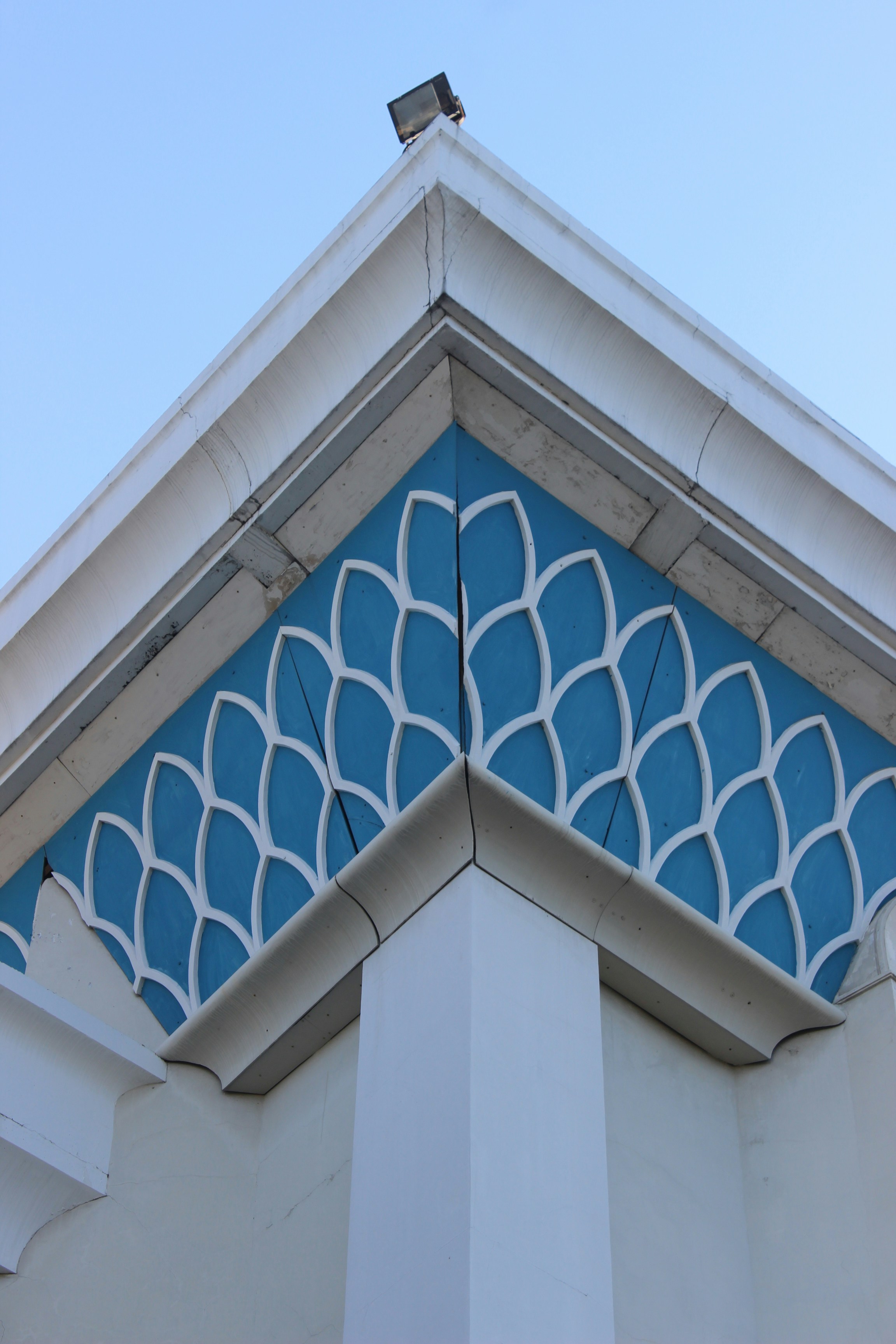 Intricate blue and white geometric patterns adorn the corner of a building, showcasing a blend of traditional and modern architectural styles.