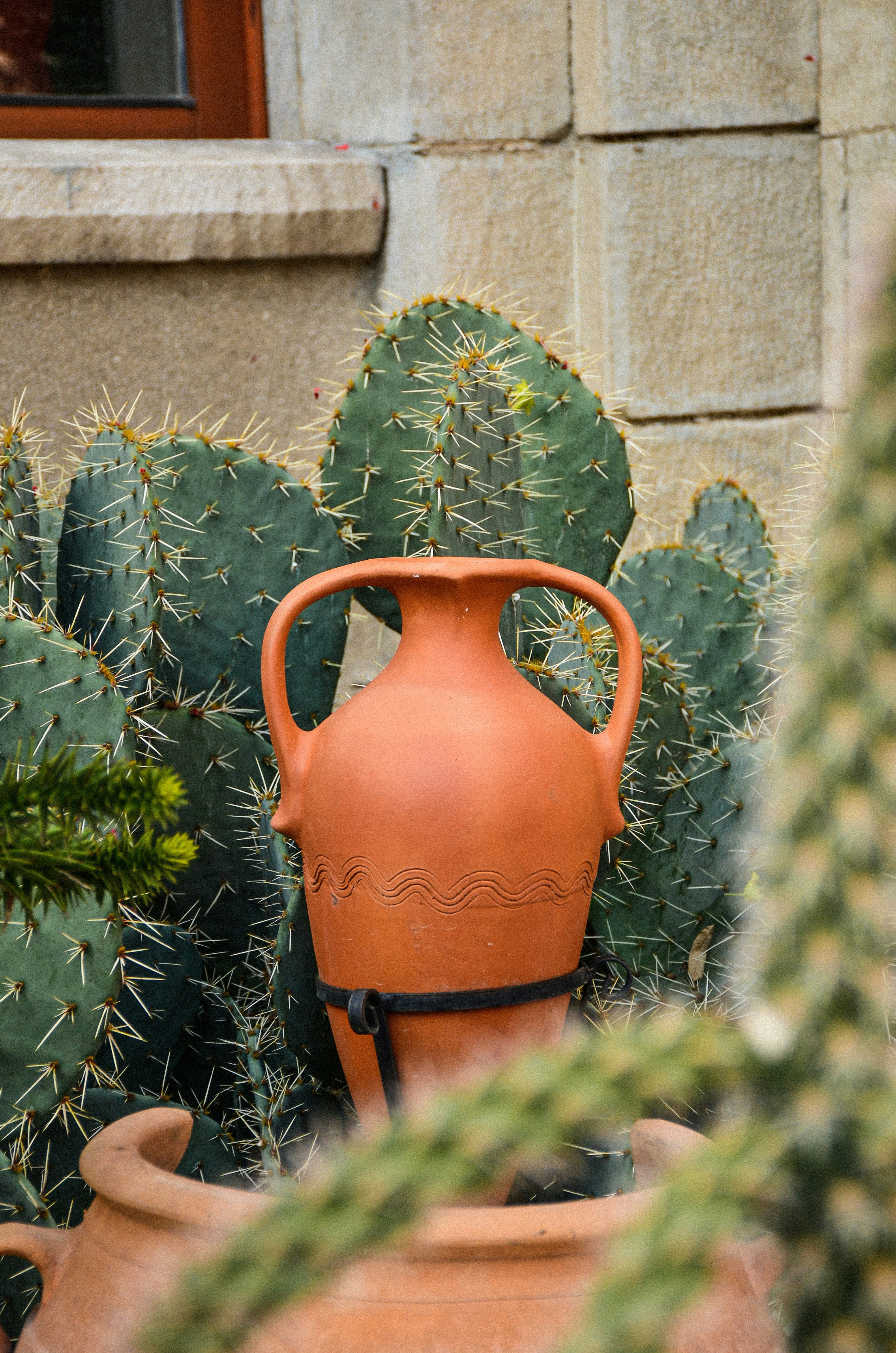 a large orange vase sitting next to a cactus