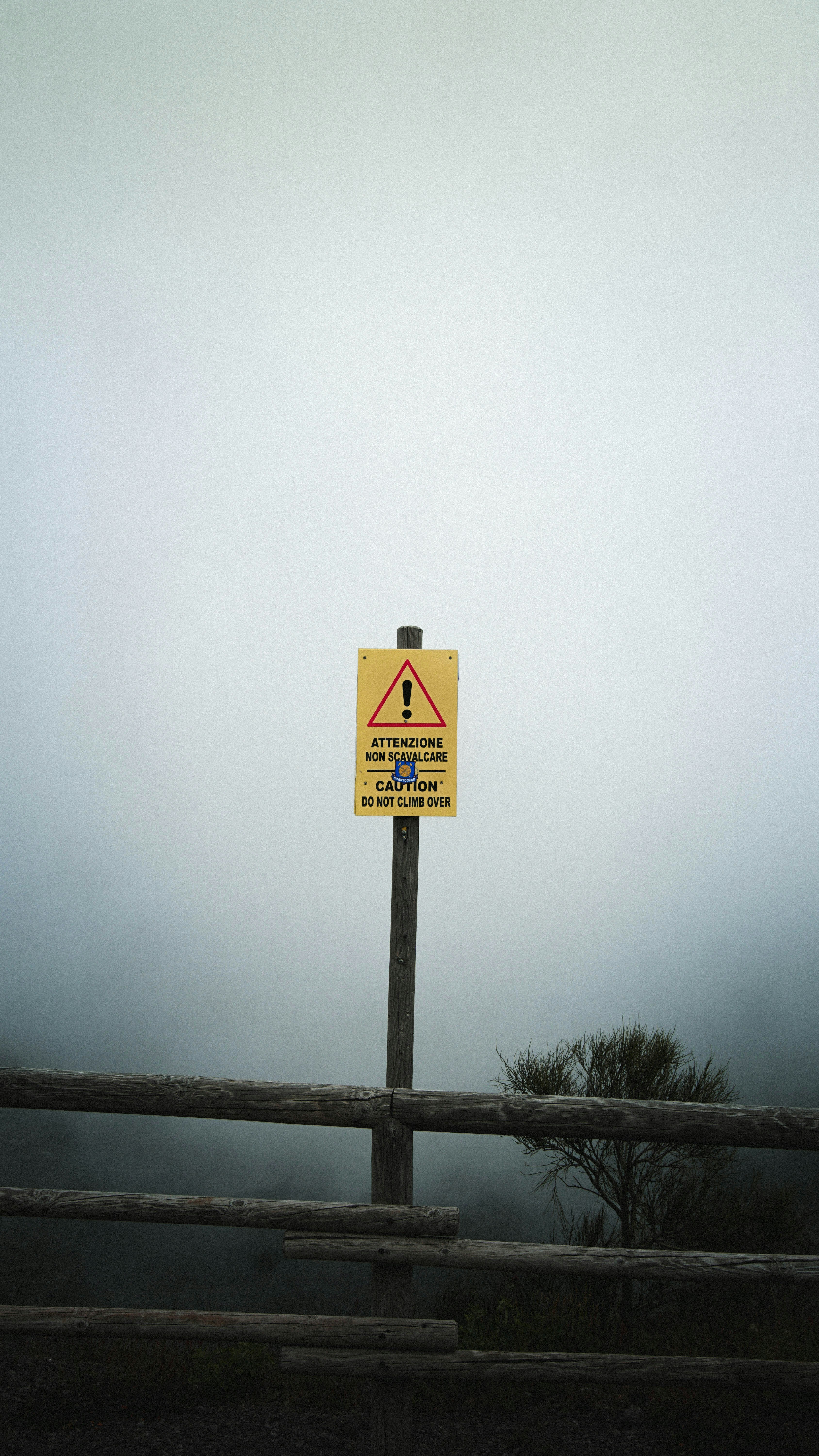 Mist-Wrapped Warning Post Over a Quiet Cliffside Fence