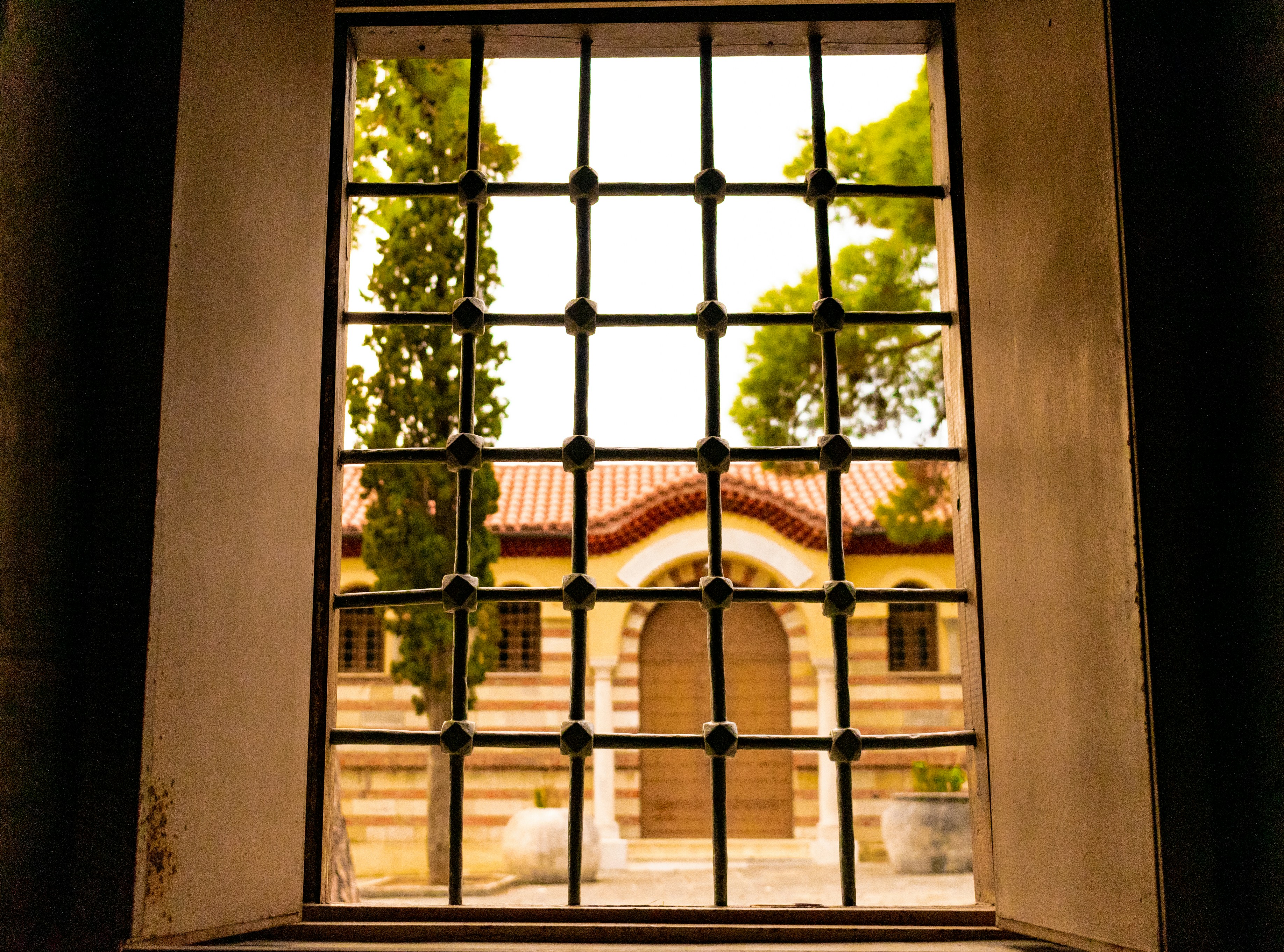 A window with bars on it and a building in the background photo – Free ...