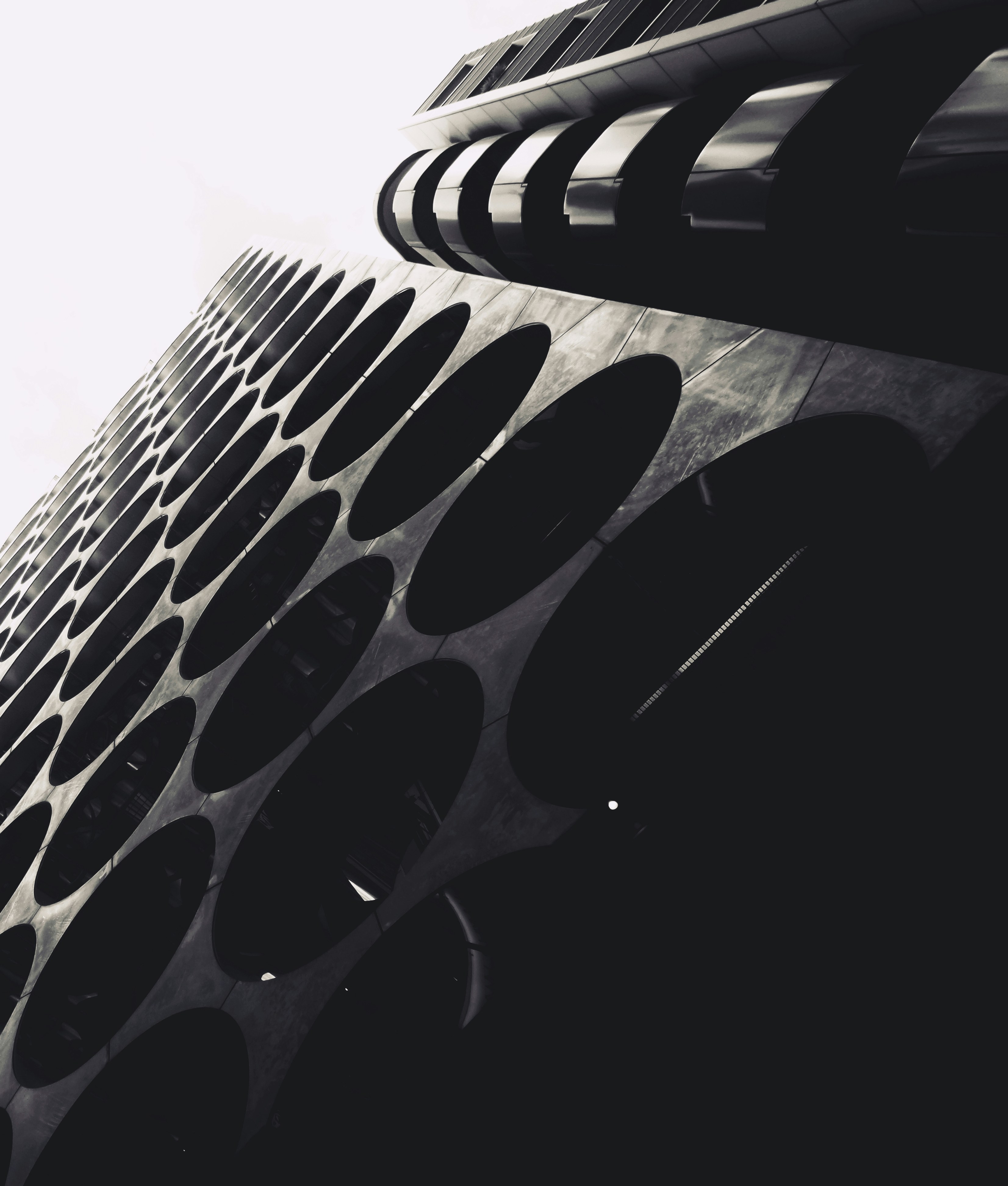 Abstract view of a building's façade featuring large circular openings, showcasing a blend of light and shadow.
