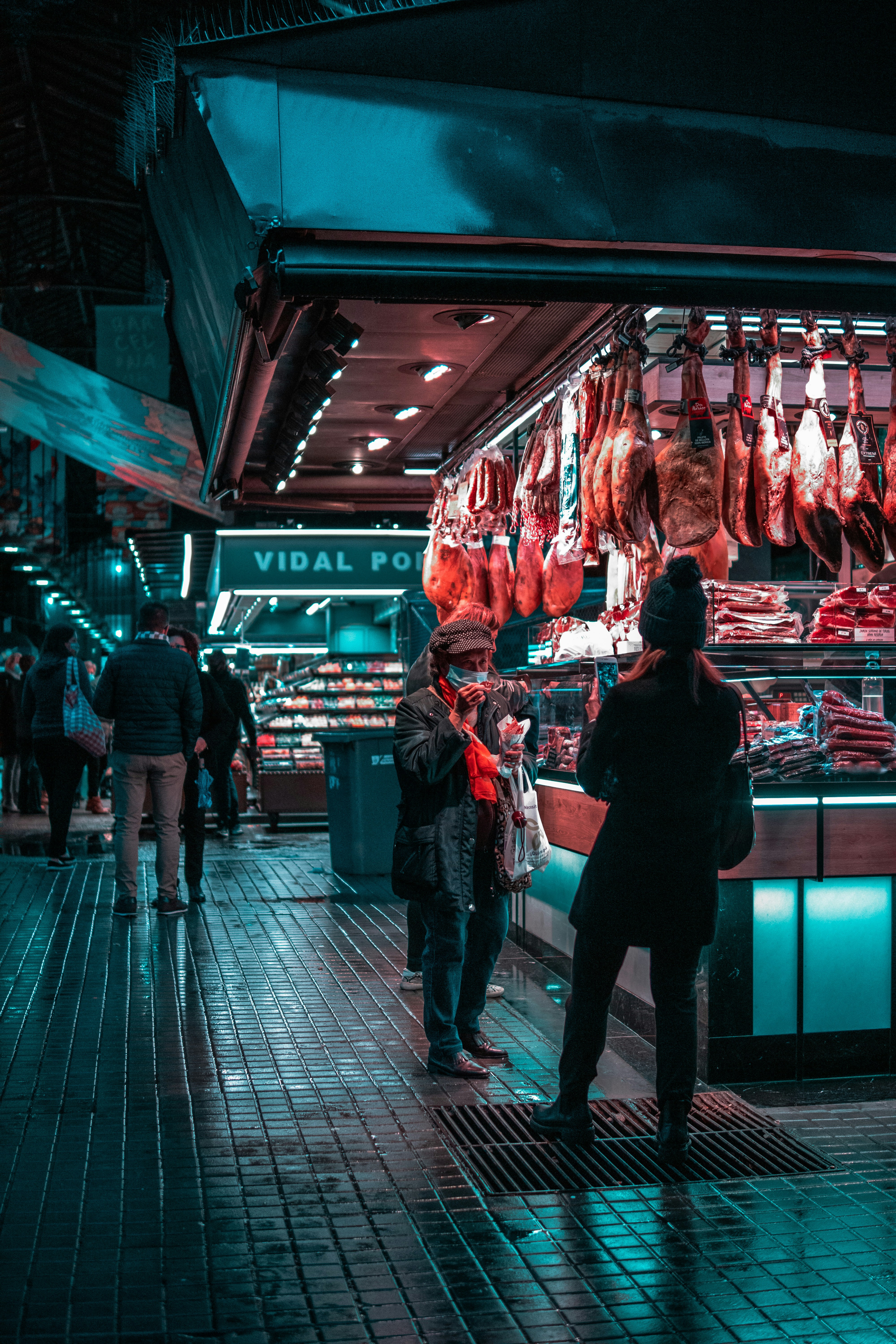 A group of people standing in front of a meat stand photo – Free Street ...