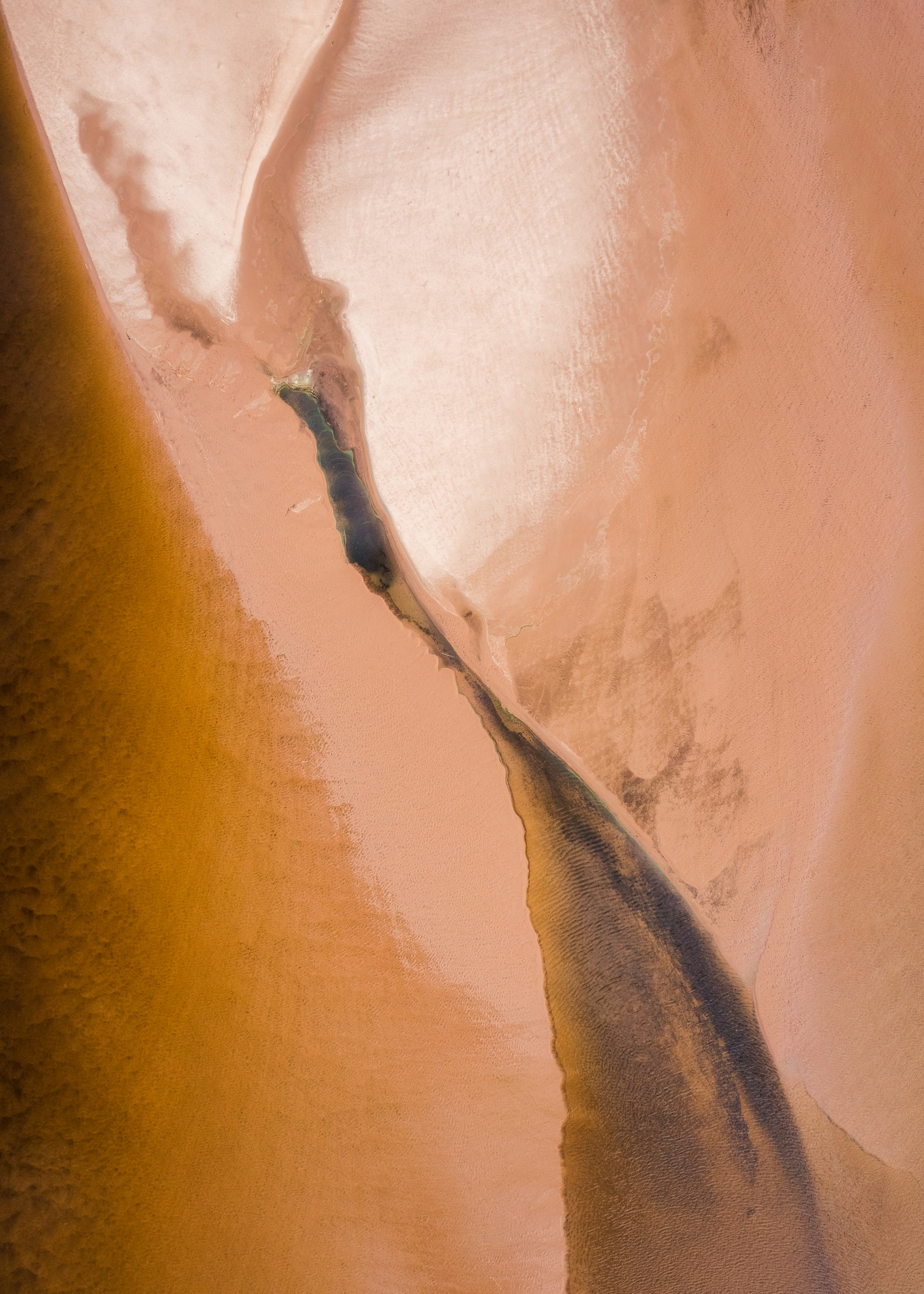 Aerial view showcasing the intricate patterns of sand and water, revealing a natural river meandering through the desert landscape.