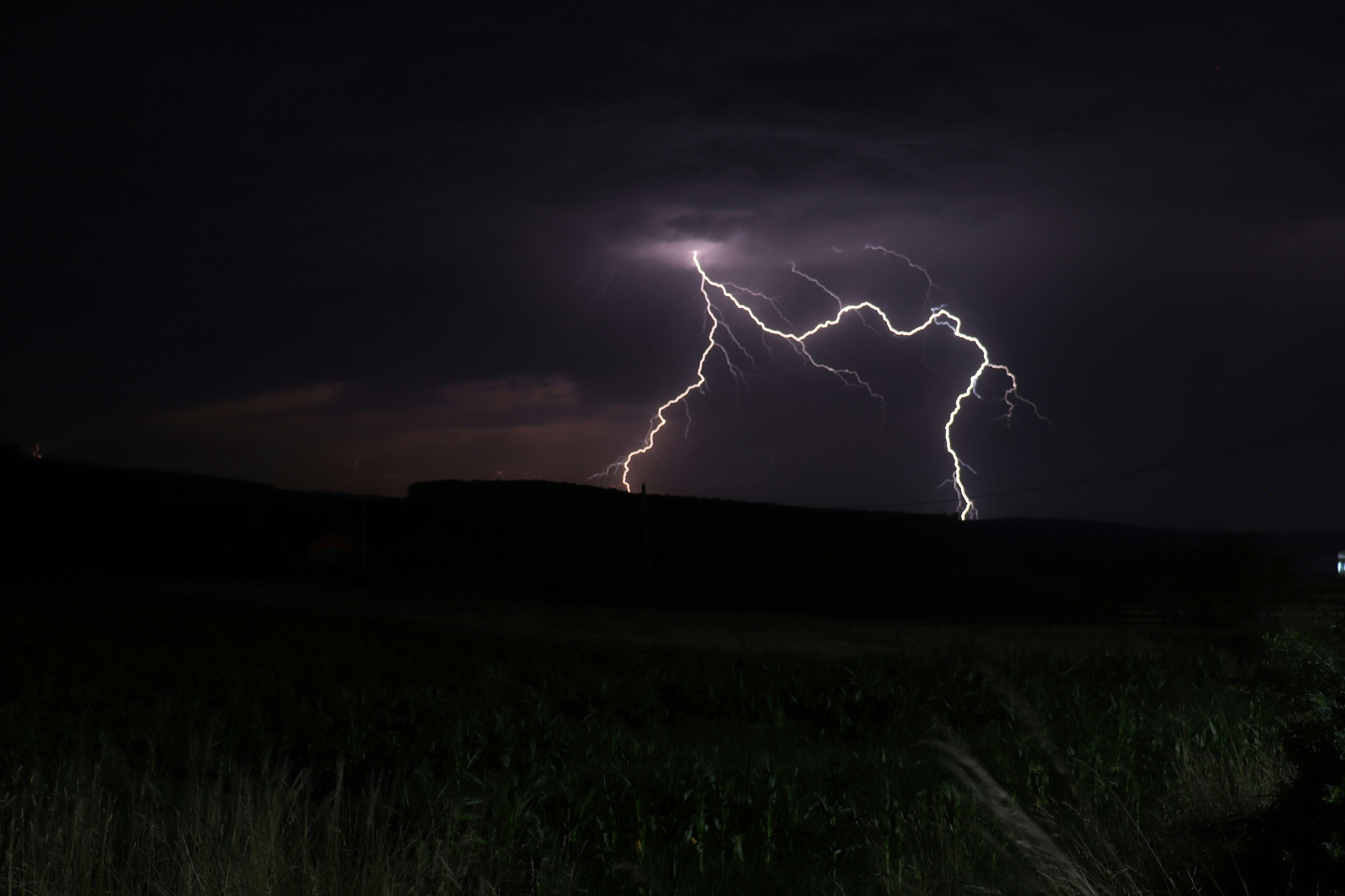 A lightning bolt hitting over a field at night photo – Free Weather ...