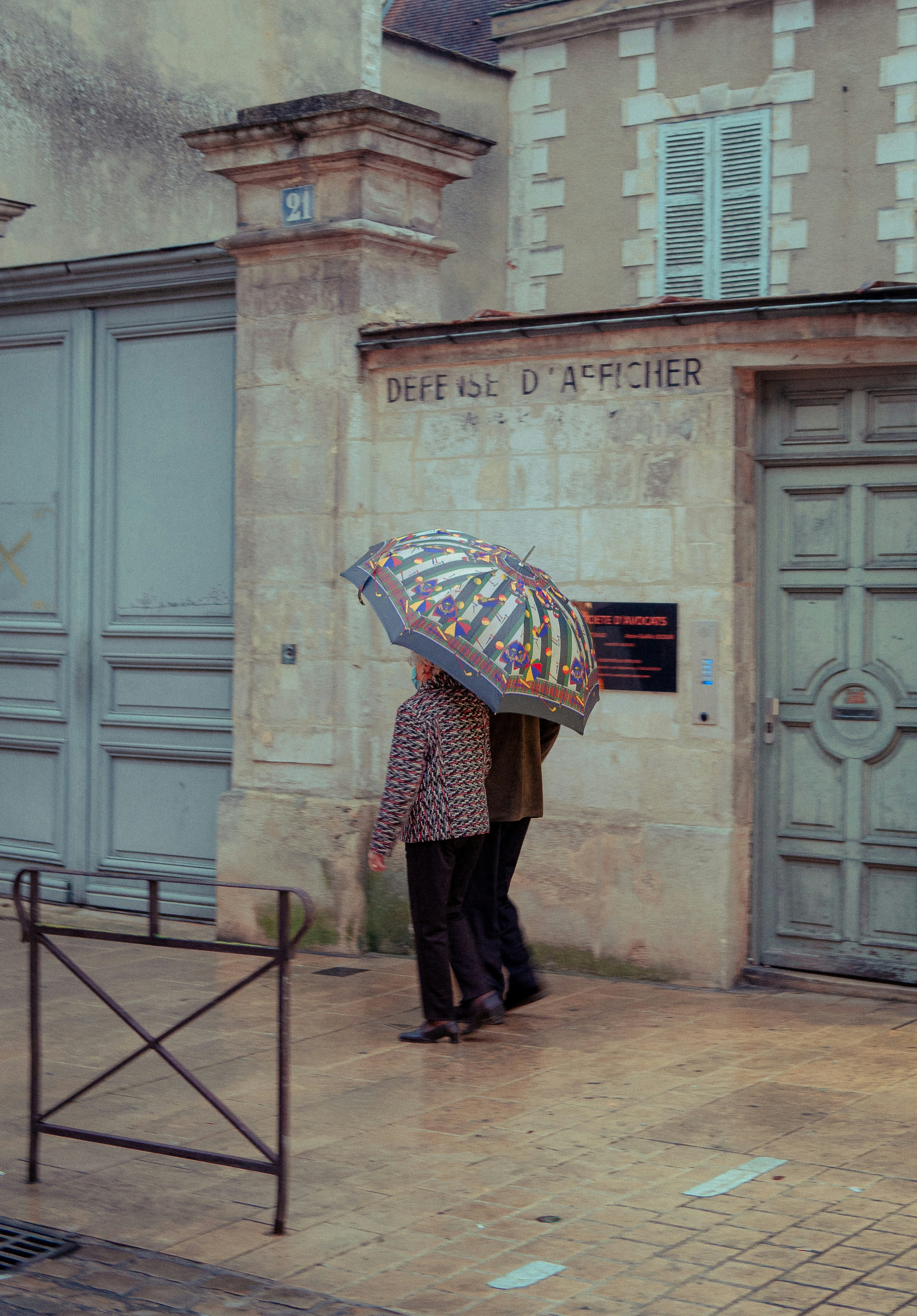 Two Umbrellas on a Rainy Rue: A Quiet Moment by the Stone Facade