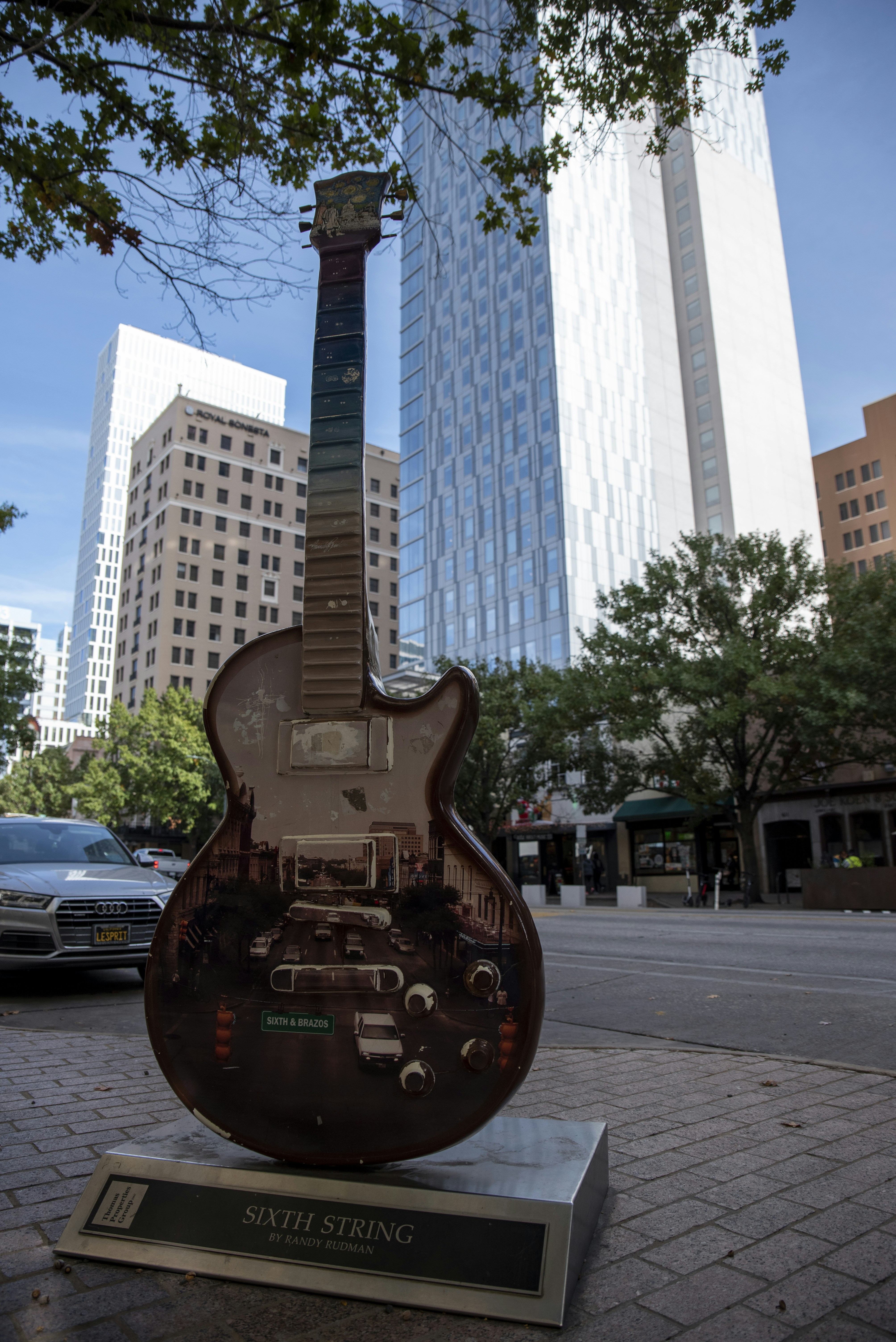 Sixth String in the City: A Rusted Guitar Stands Tall Amid Skyscrapers