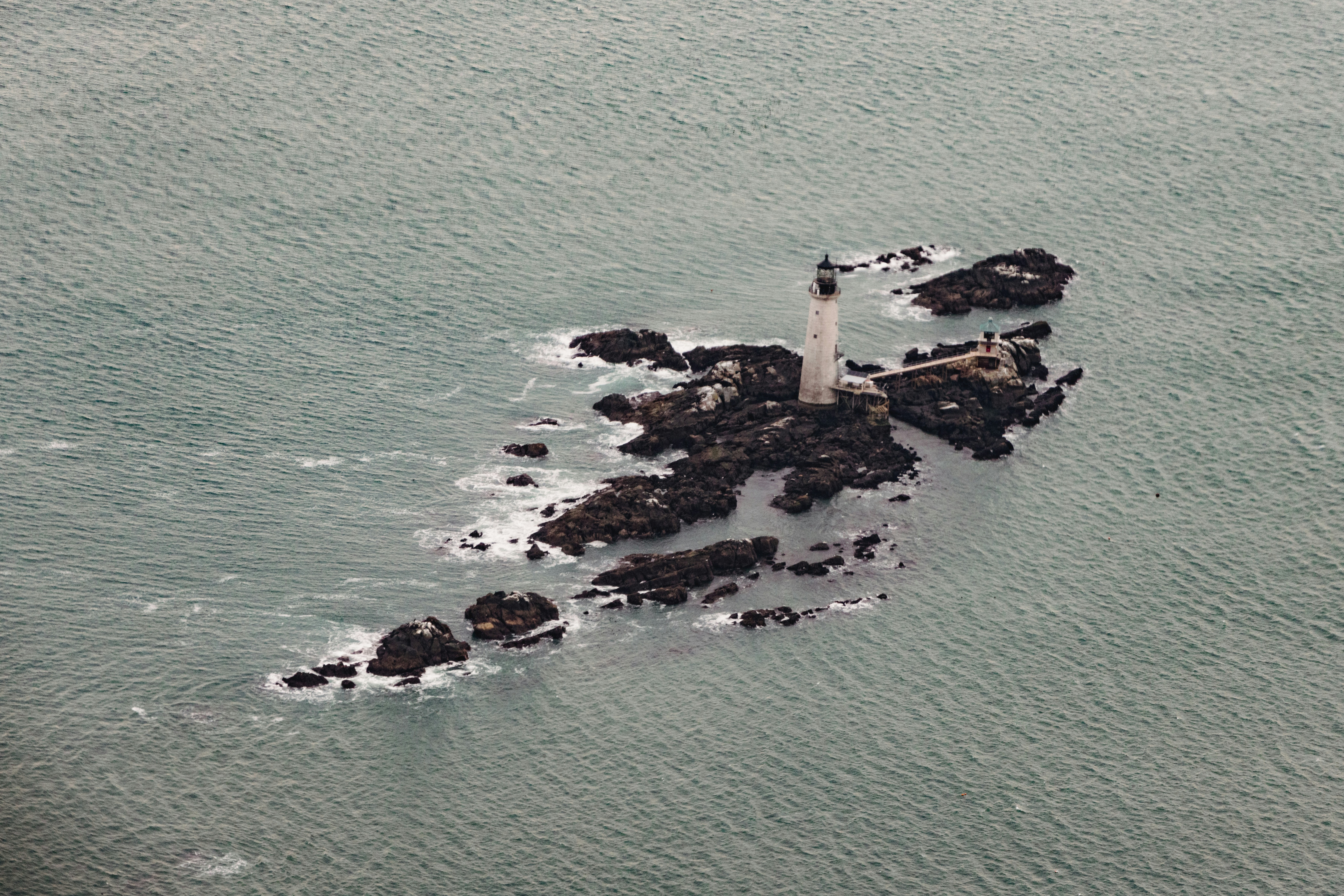 an aerial view of a lighthouse in the middle of the ocean