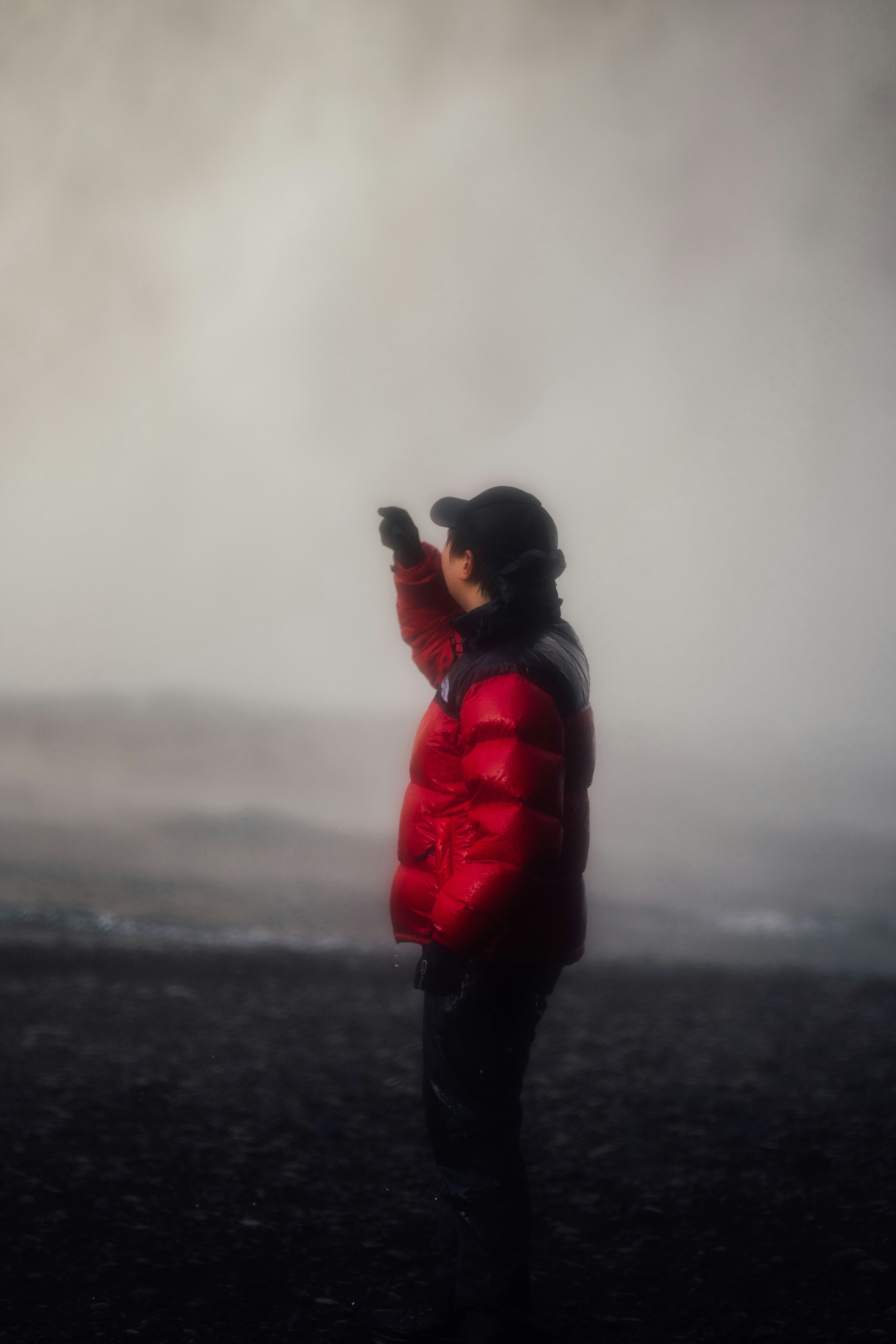 Crimson in the Mist: A lone observer anchors a fog-washed shoreline