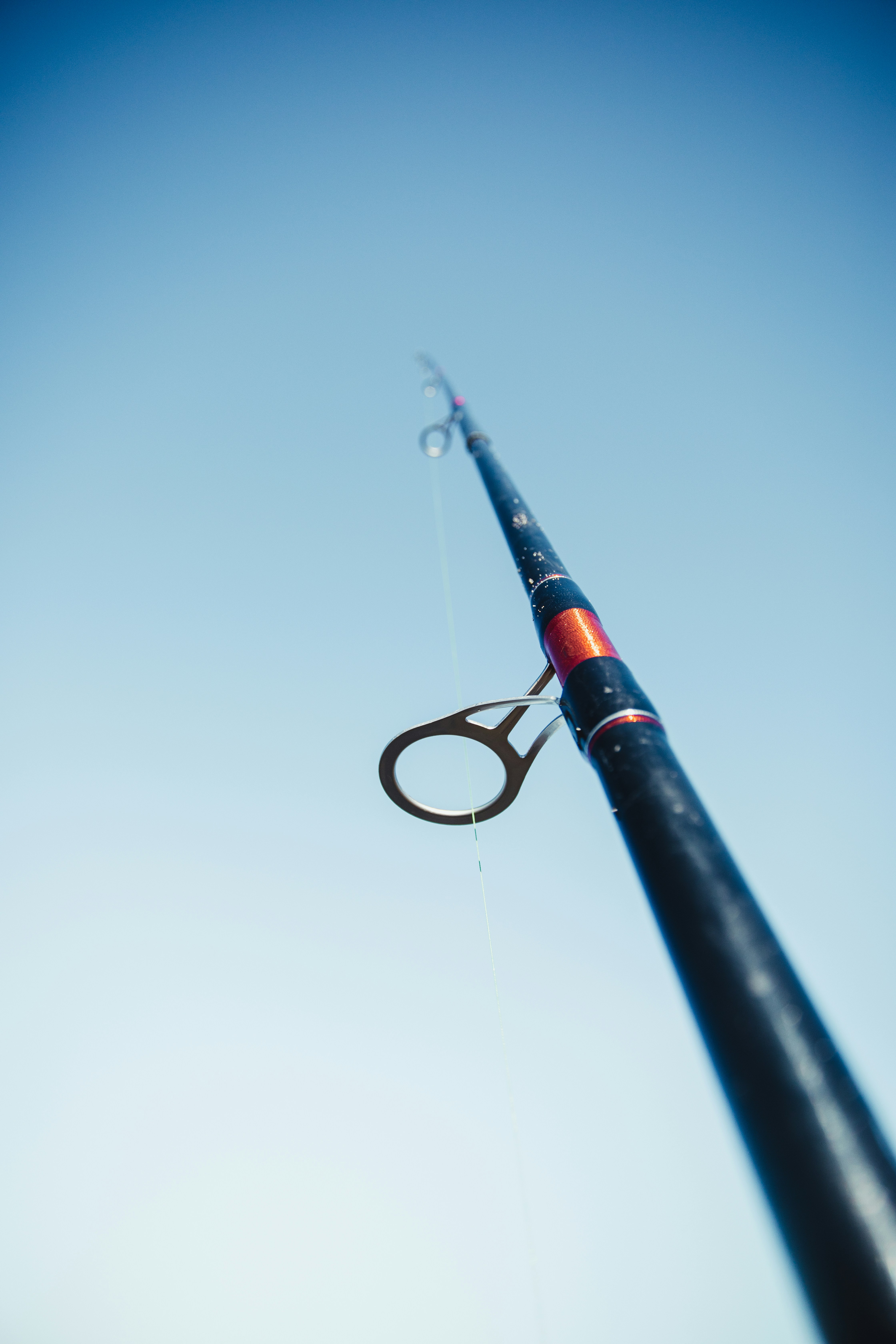 Threaded Light: Close-Up of a Fishing Rod Reaching into a Clear Blue Sky