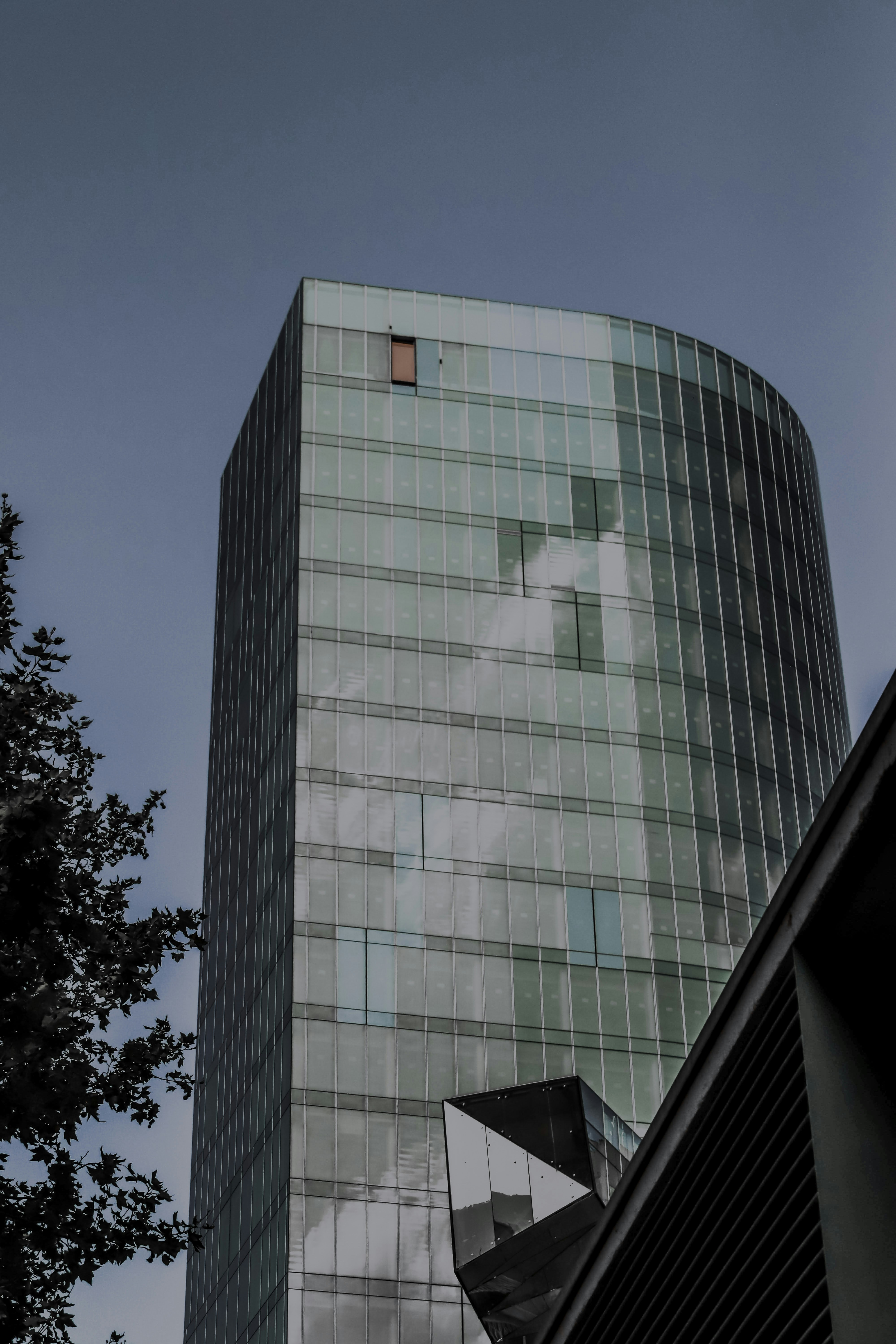 A tall glass building with a clock on the side of it photo – Free ...