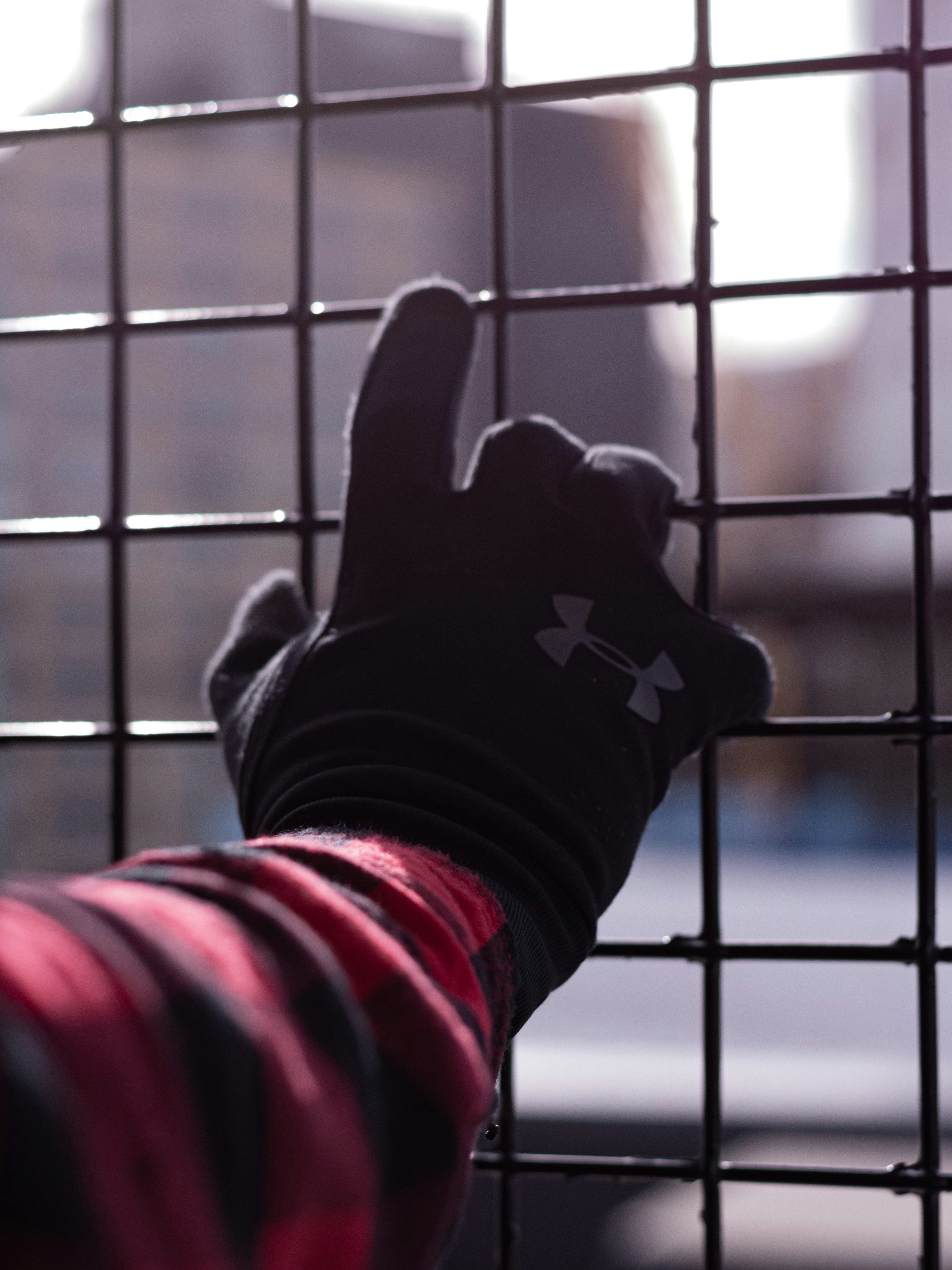 Urban Grip Through the Grid: A Gloved Hand Reaches Toward the City