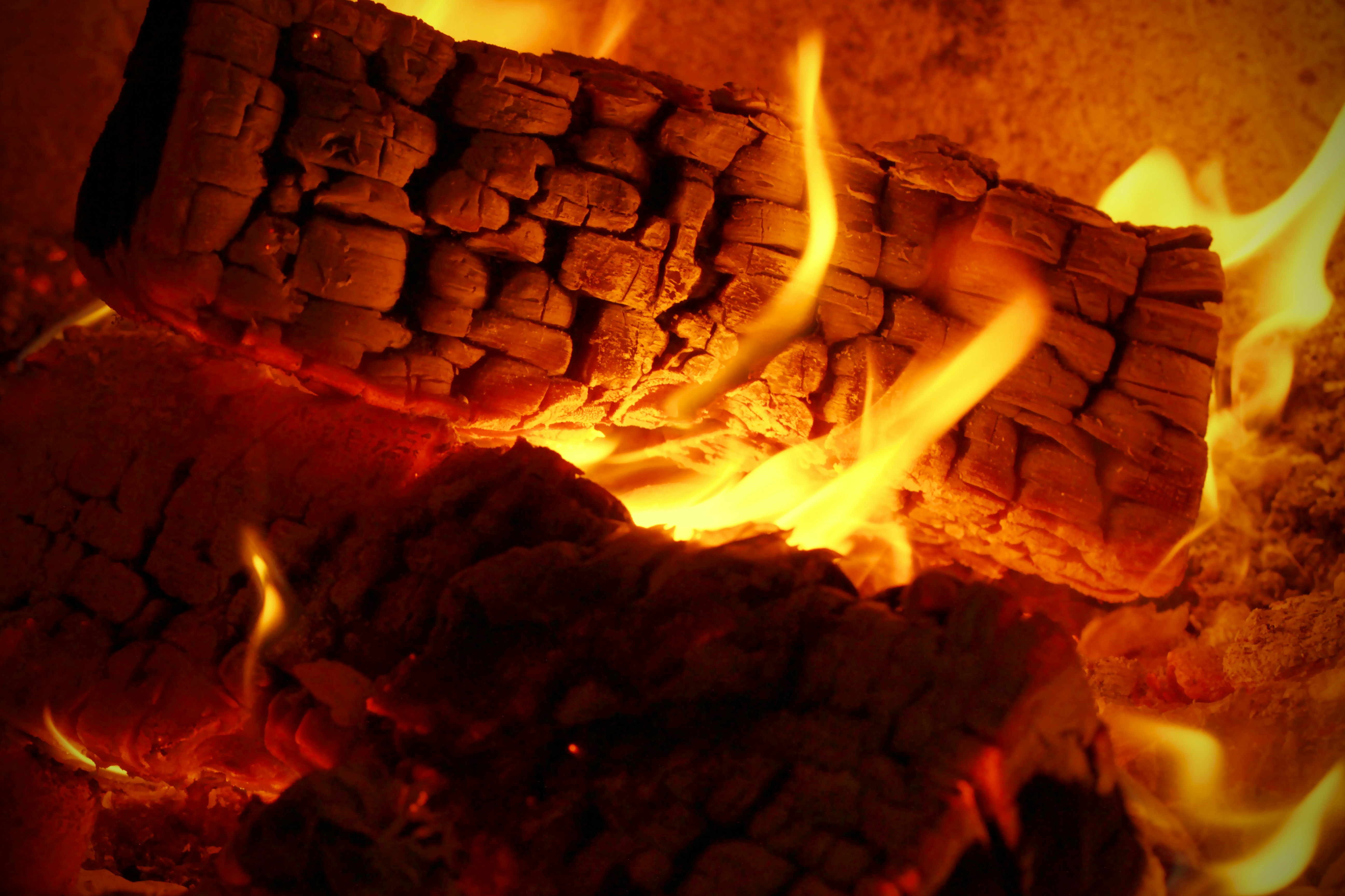 Burning logs create a mesmerizing display of flames and glowing embers, highlighting the warmth of a cozy fire.