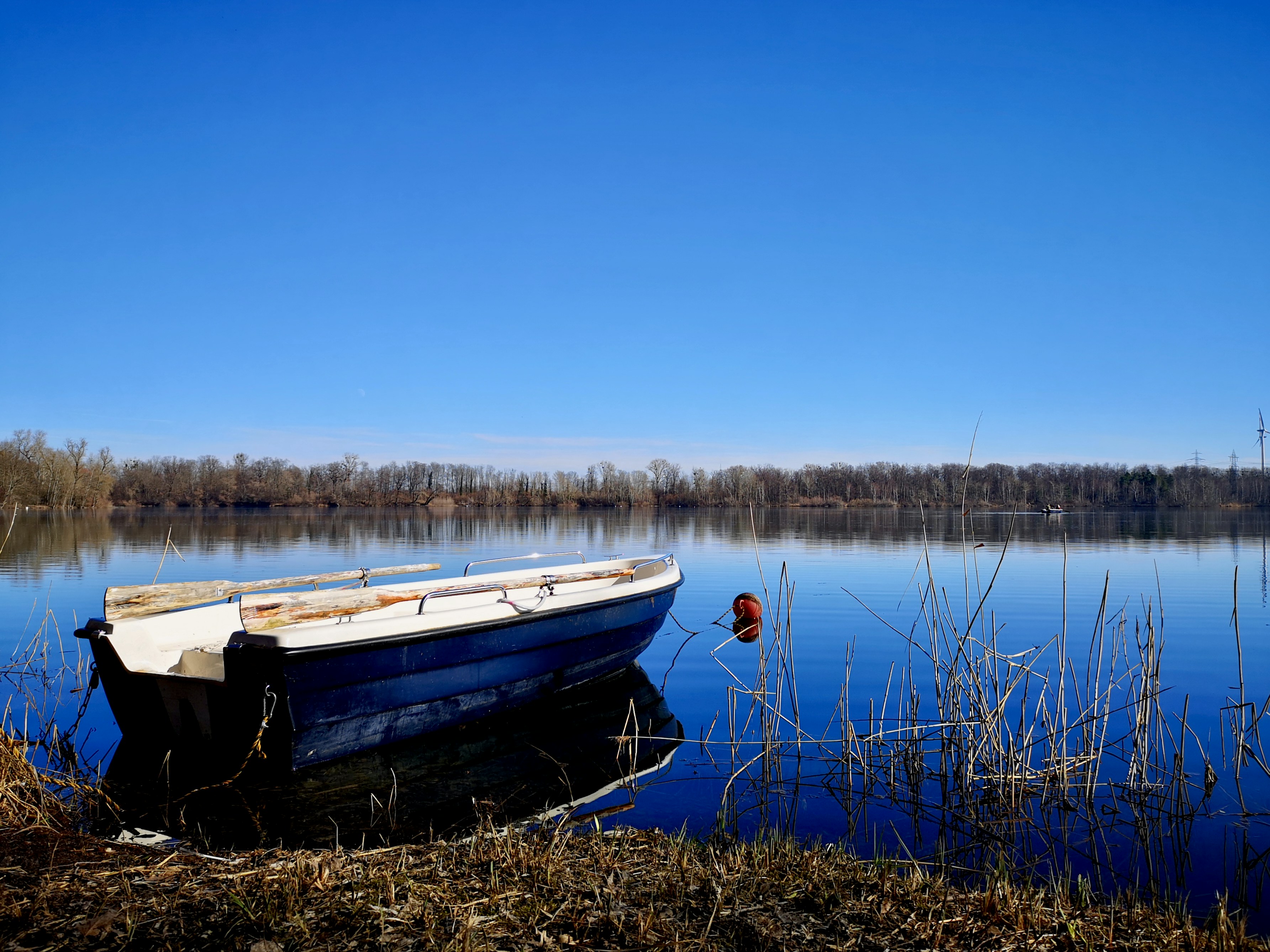 Azure Quiet: A lone boat at the edge of a glassy lake