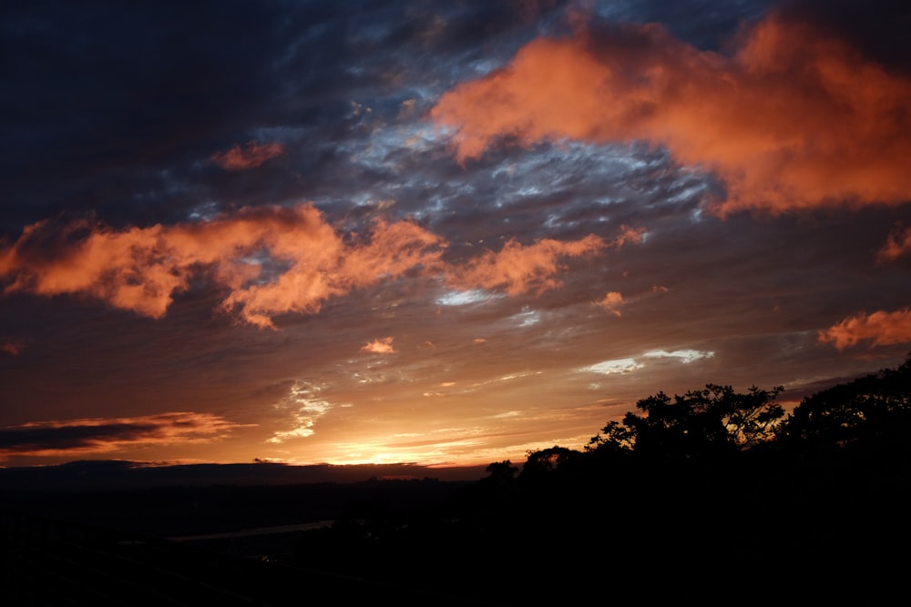 Un coucher de soleil avec des nuages et des arbres au premier plan ... Un coucher de soleil avec des nuages et des arbres au premier plan ...
