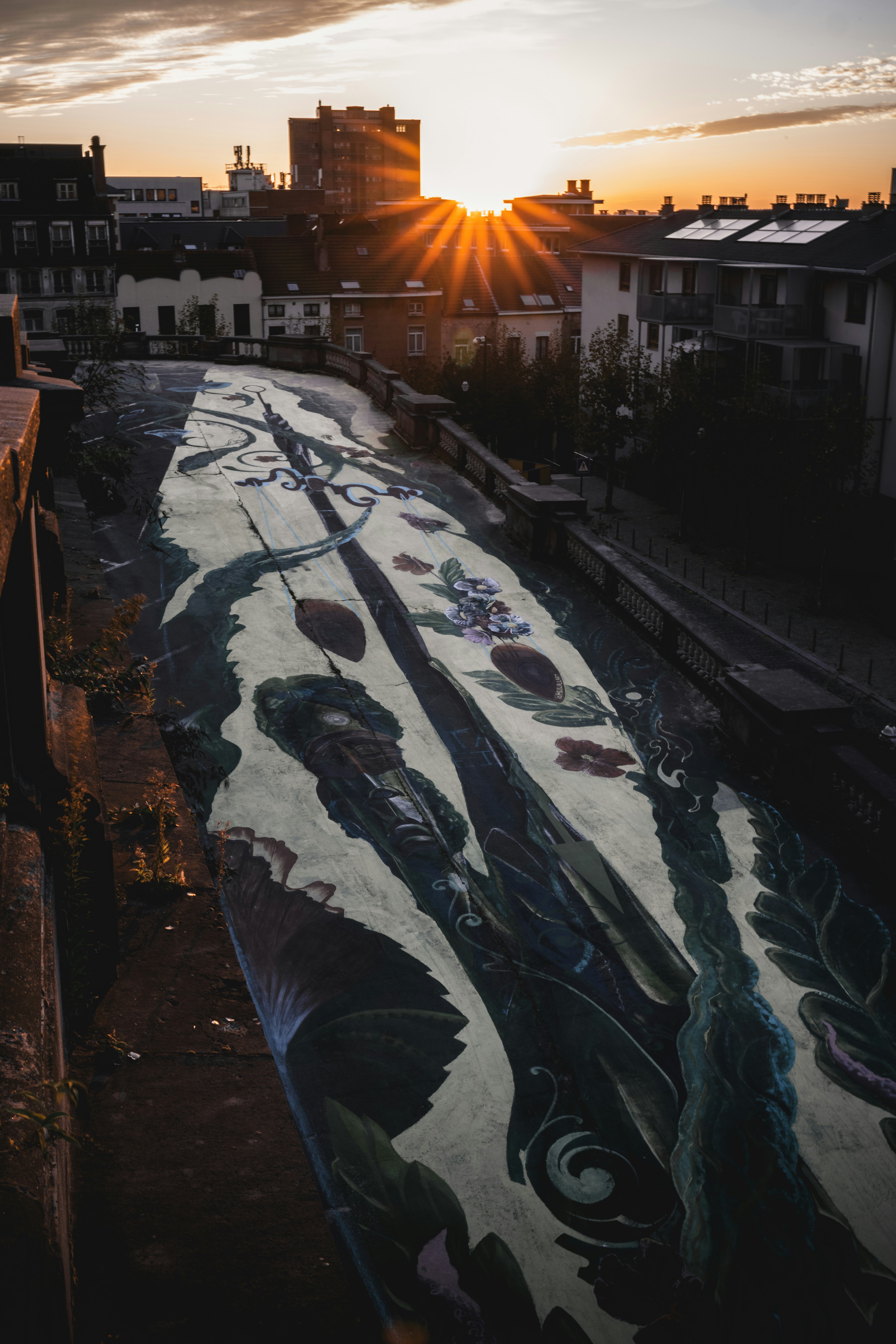 Sunrise over a muraled canal: dawn light carves shadows on art beneath the city