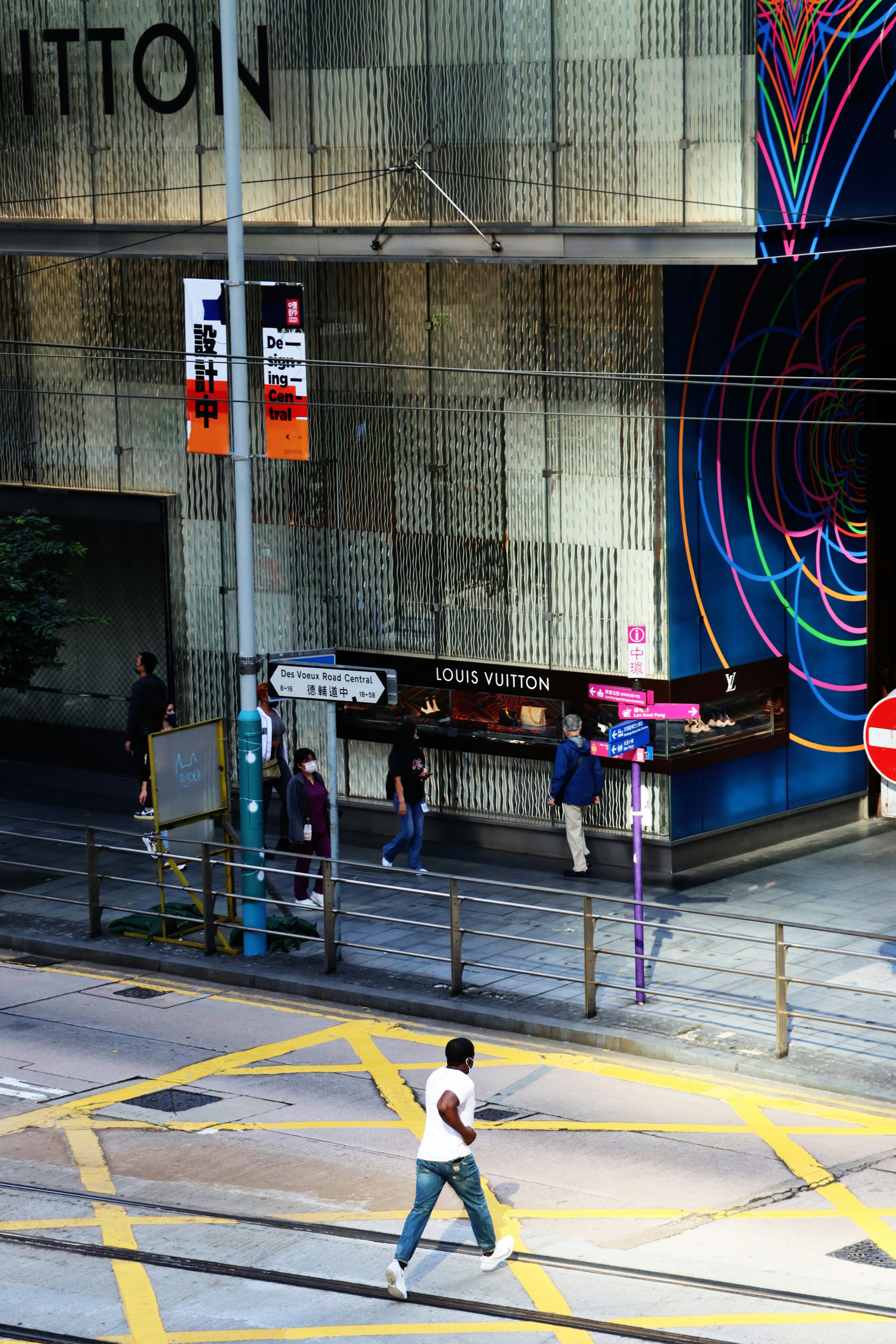 Crossing Under Neon Arcs: Pedestrian in Front of a Louis Vuitton Facade