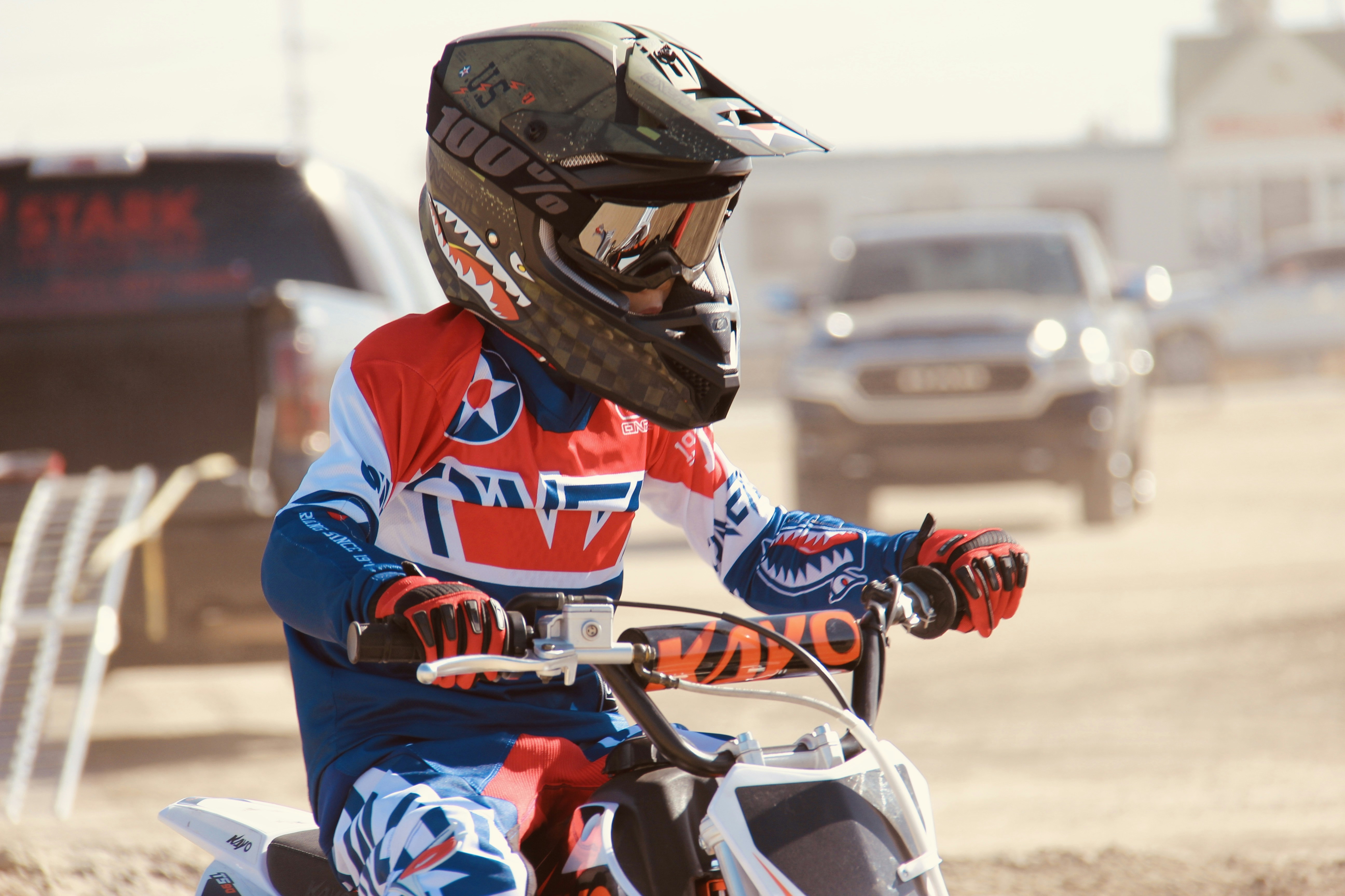 Child motocross rider in vibrant gear navigating a dusty track, showcasing determination and skill.