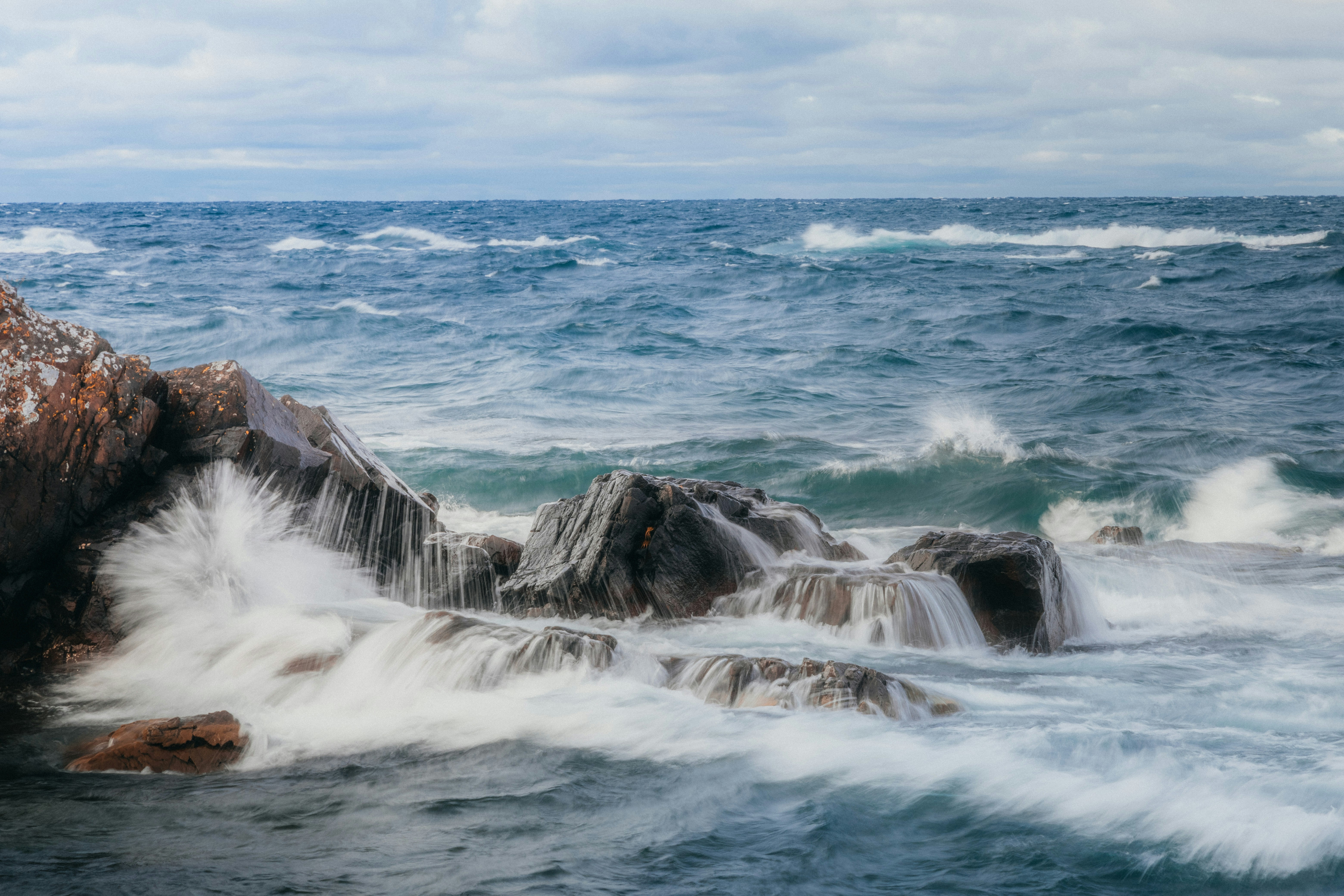 A large body of water surrounded by rocks photo – Free Grey Image on ...