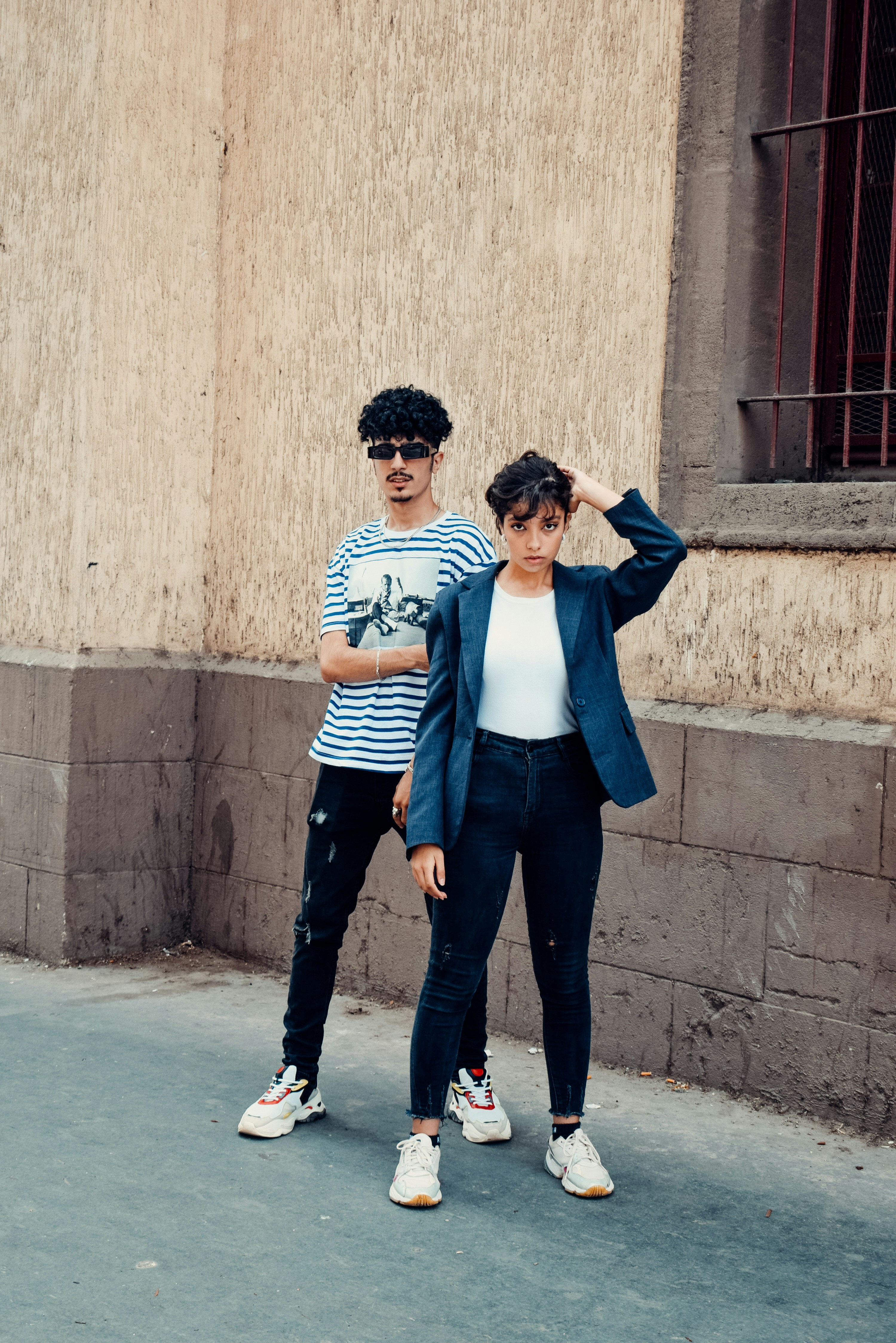 Stride and Style: Striped Tee meets Blazer Against Weathered Brick