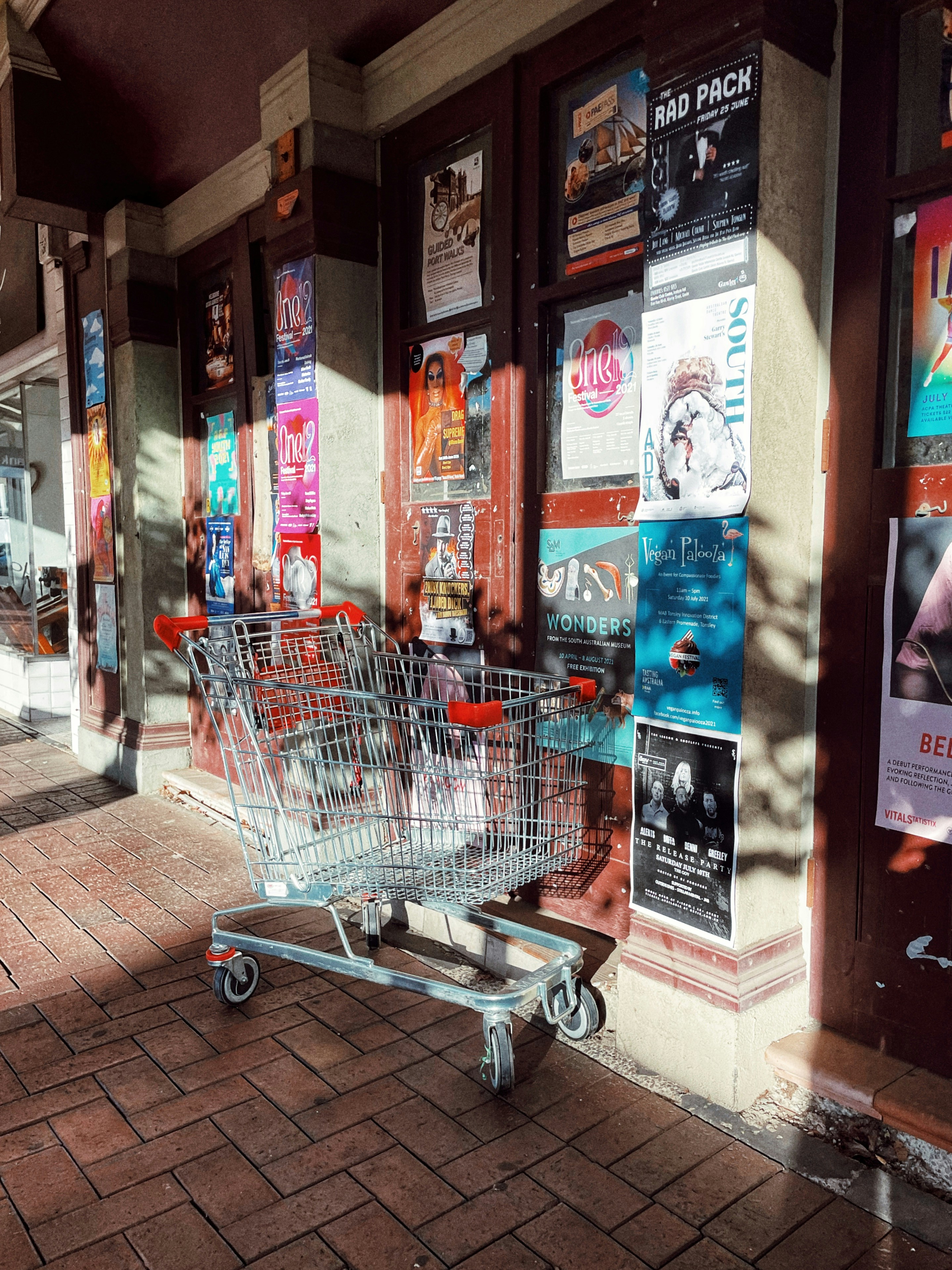 Cart in the Shadowed Street Gallery: A Tiled Sidewalk Framed by Poster Walls