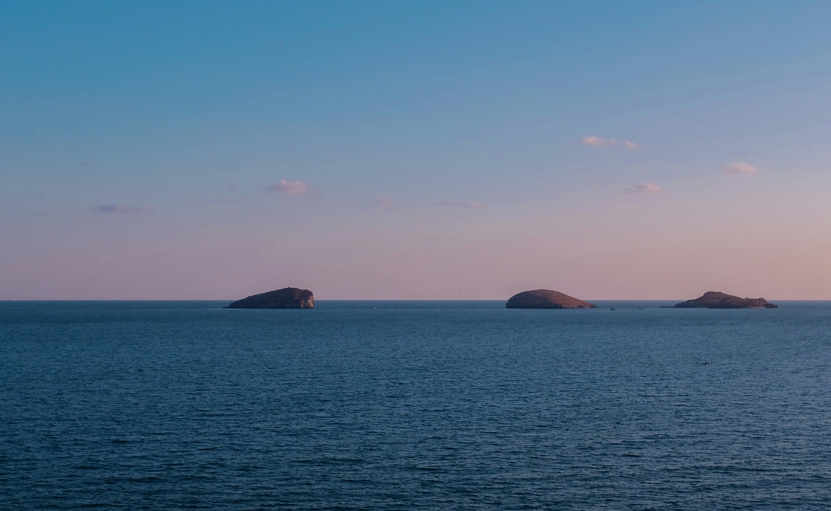 A body of water with two small islands in the distance photo – Free ...
