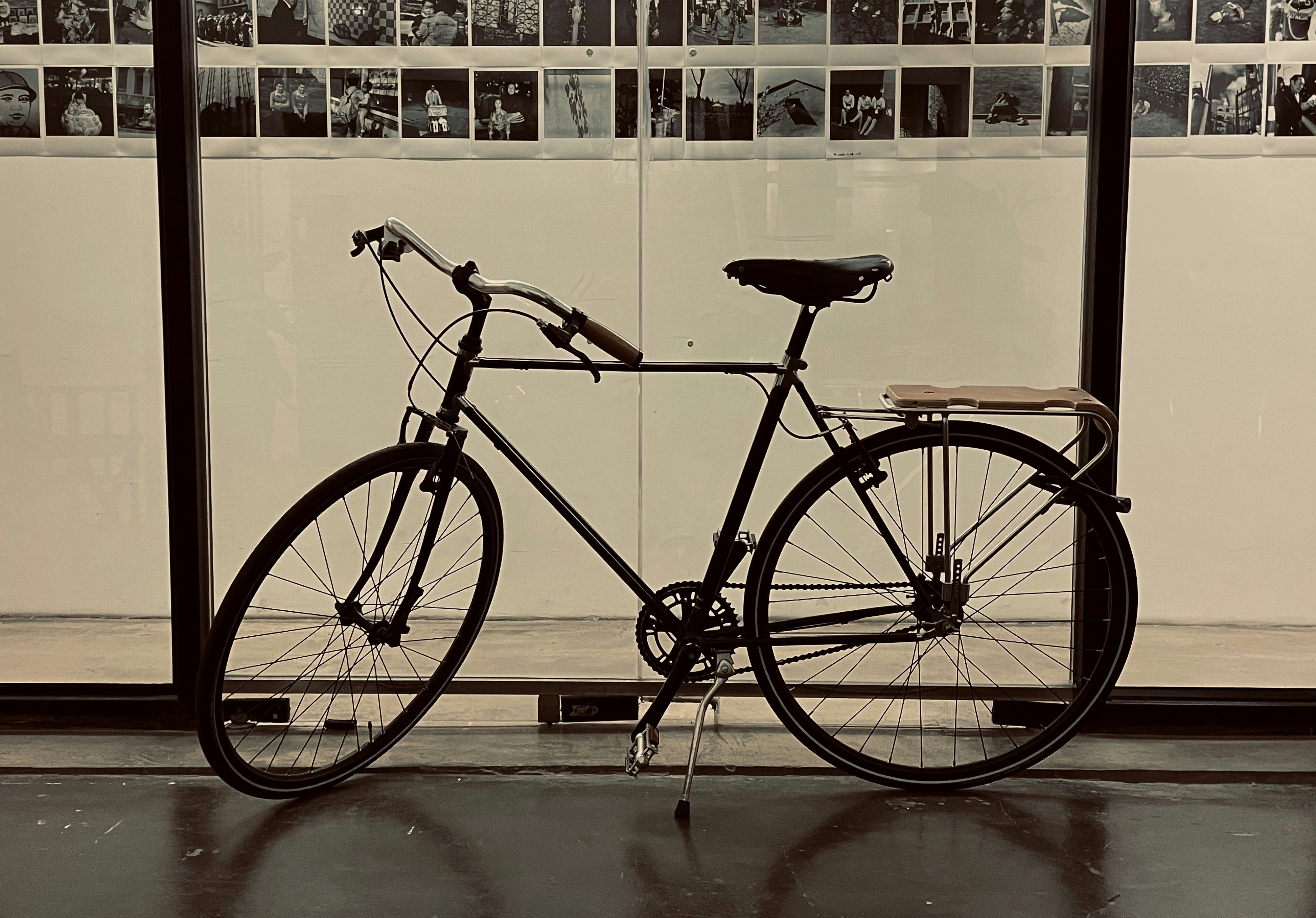 A vintage bicycle stands against a gallery wall adorned with black-and-white photographs, showcasing a blend of nostalgia and artistry.