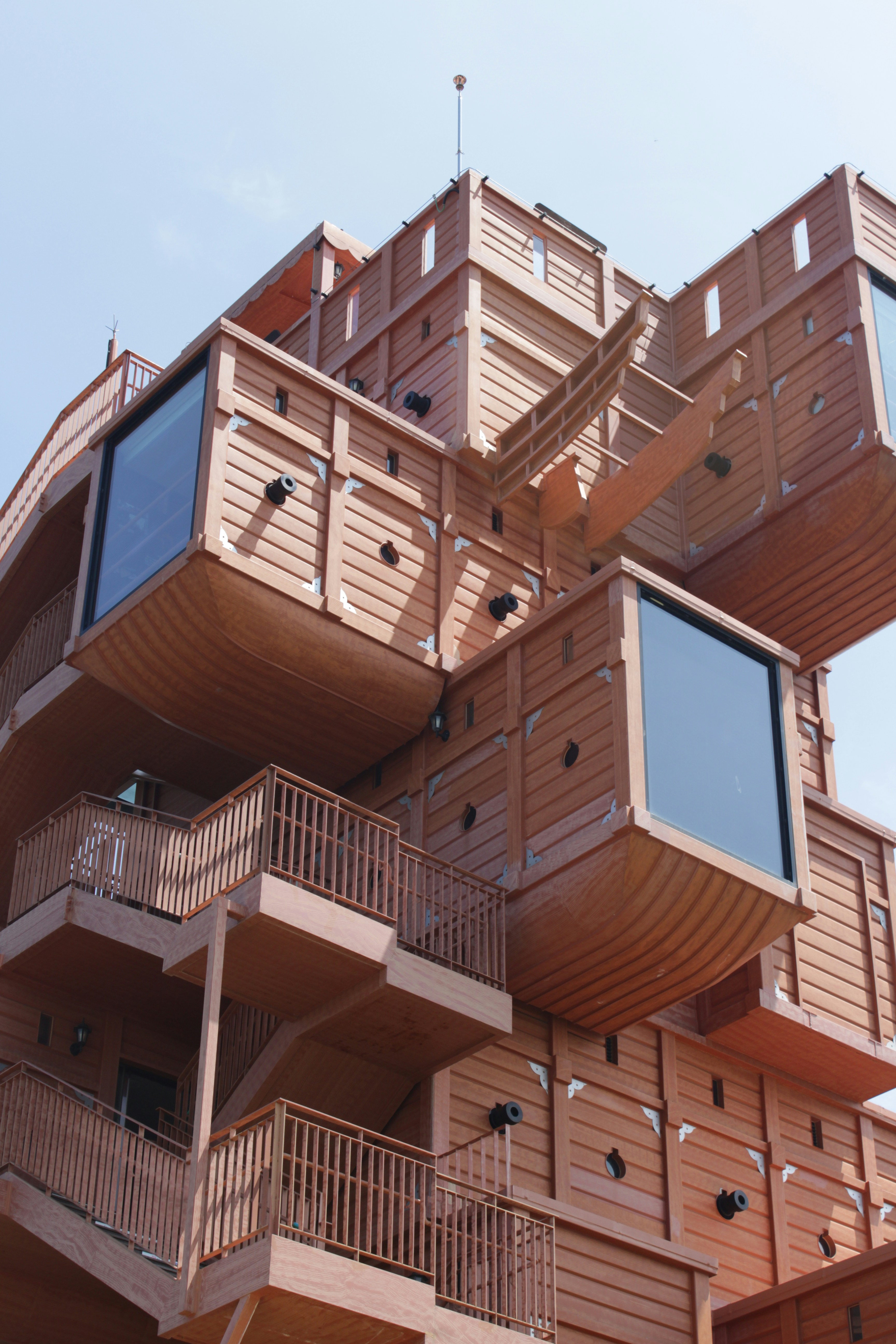 Unique wooden building featuring cantilevered balconies and large glass windows, showcasing innovative architectural design.