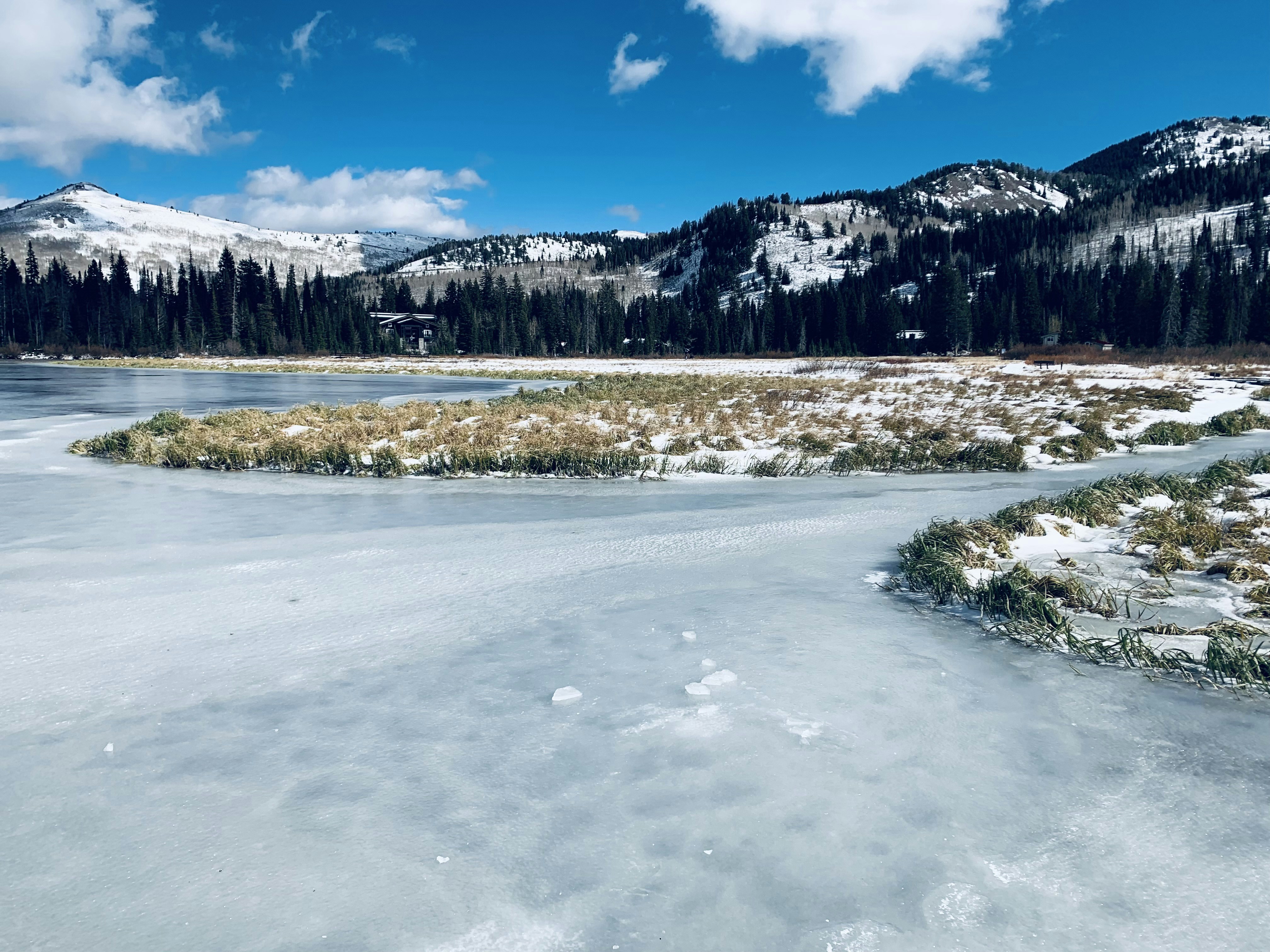 A frozen lake surrounded by snow covered mountains photo – Free Forest ...