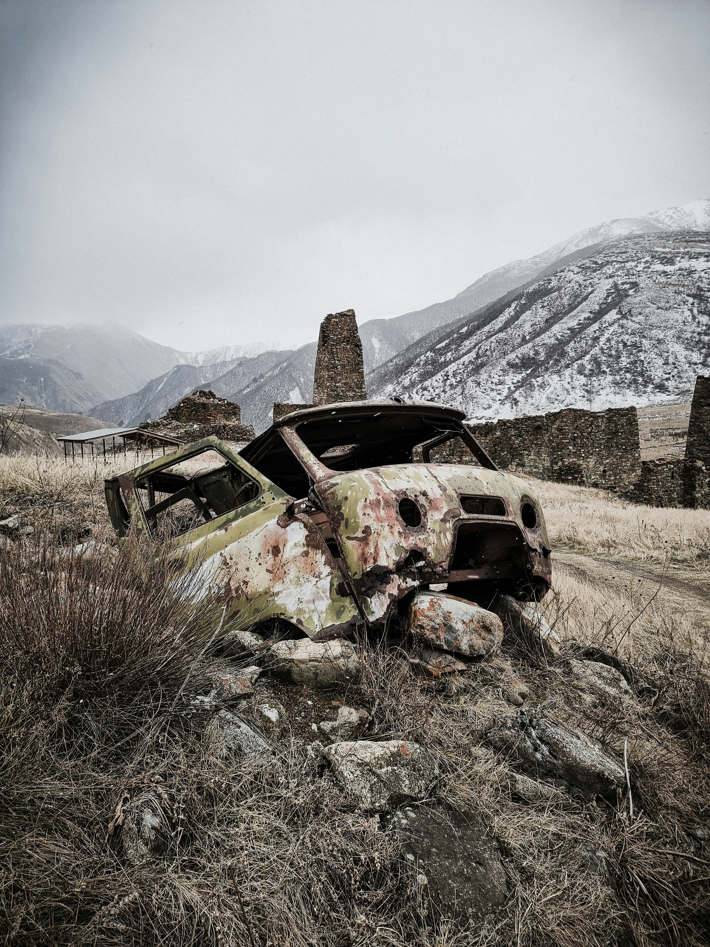 a rusted out car sitting in the middle of a field